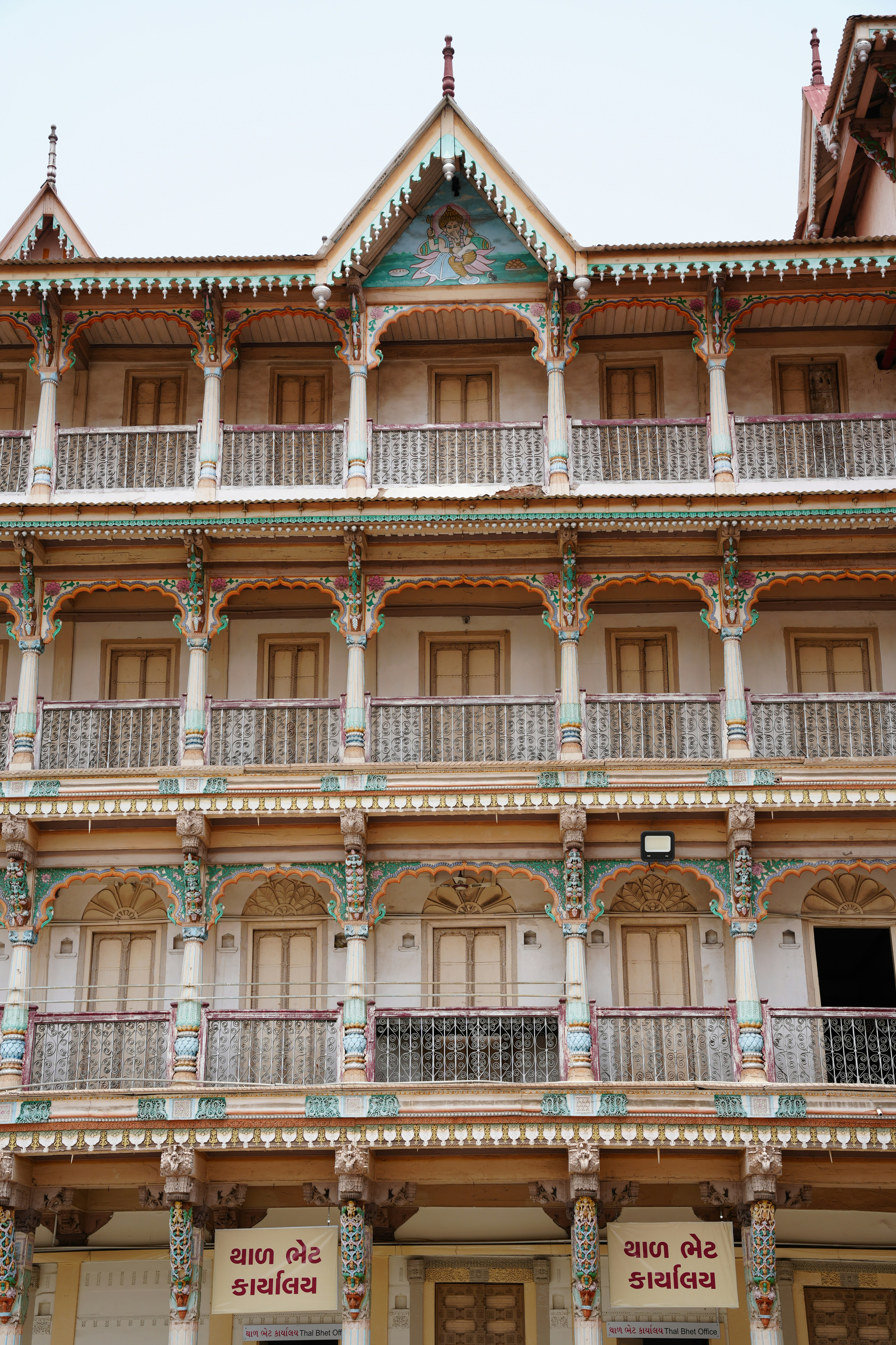 Intricate wooden balconies and vibrant motifs adorn the façade of a historical building, showcasing traditional craftsmanship and architectural elegance.