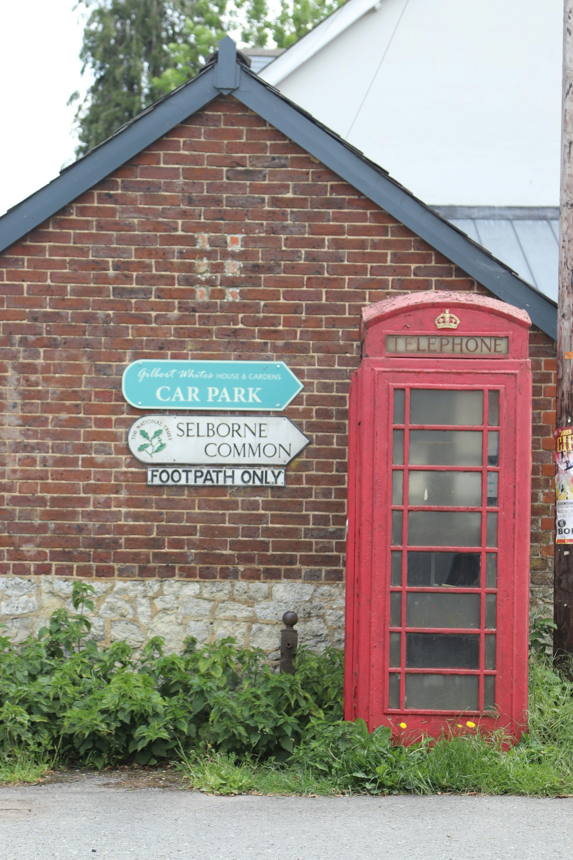 Scarlet Kiosk by the Brick Wall: A Quiet Village Telephone Stop