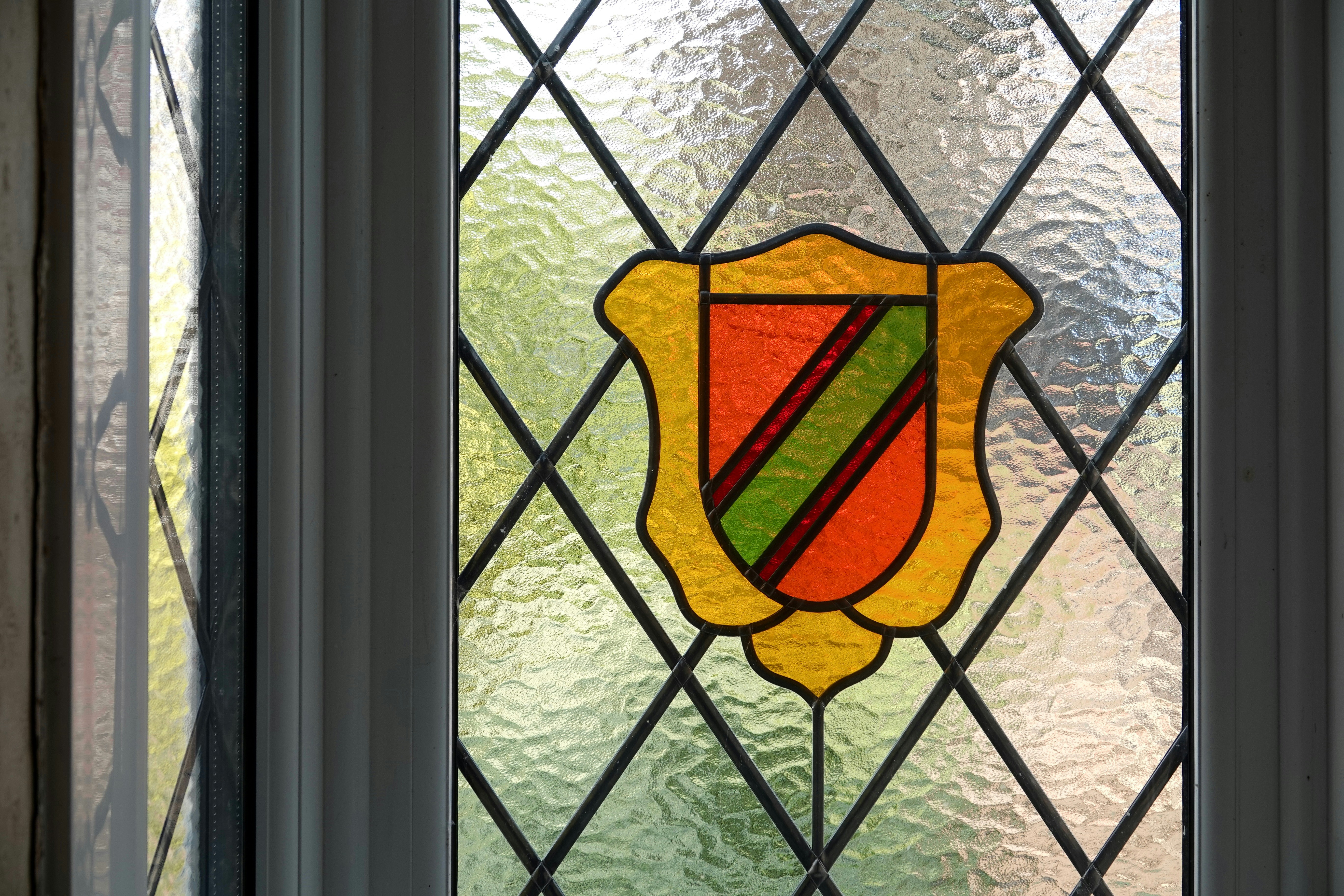 Crest in Diamond Glass: A Shield Adorned with Color in a Latticed Window
