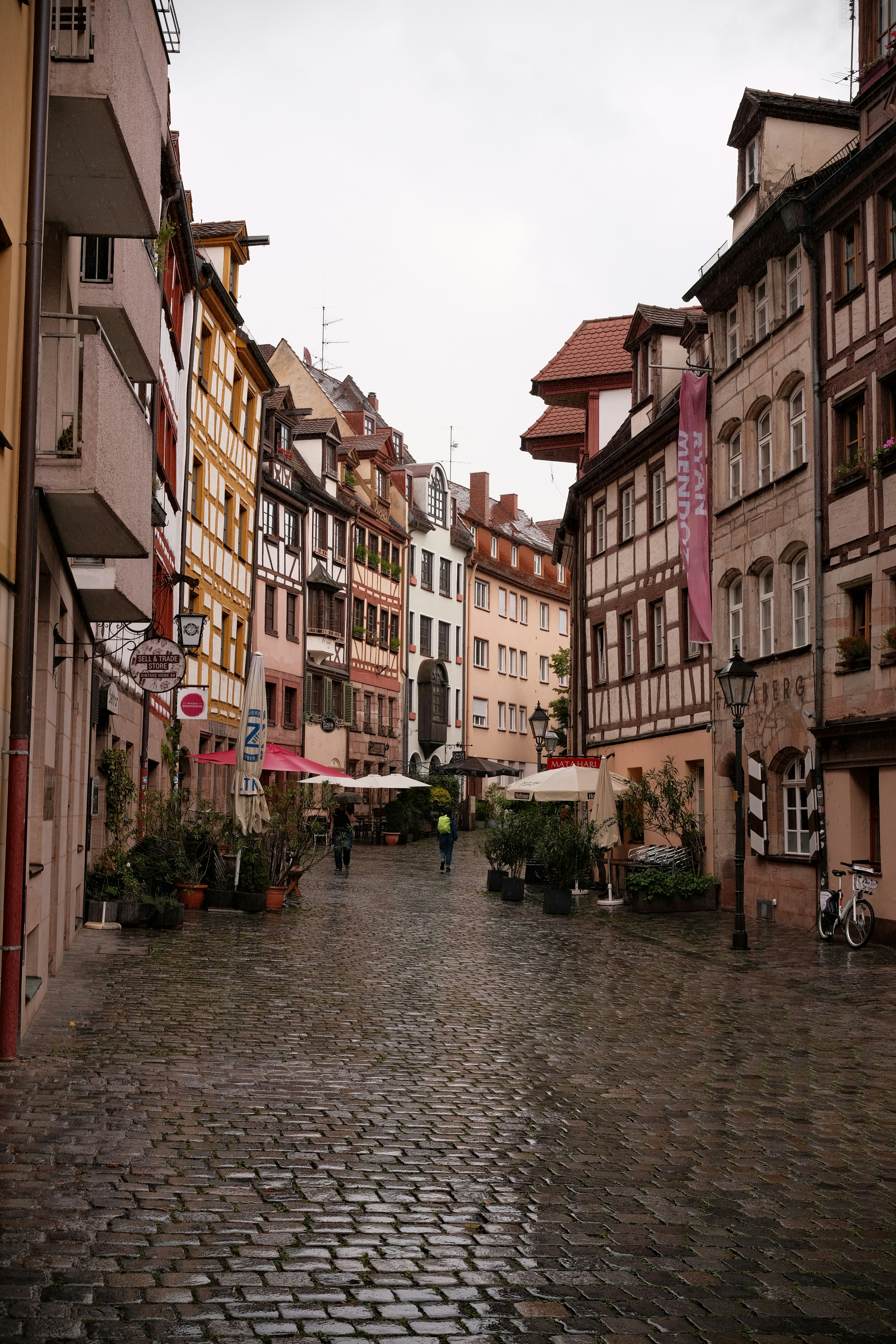Cobblestone street lined with charming buildings in a historic town on a rainy day | Cobblestone street in a charming european city.