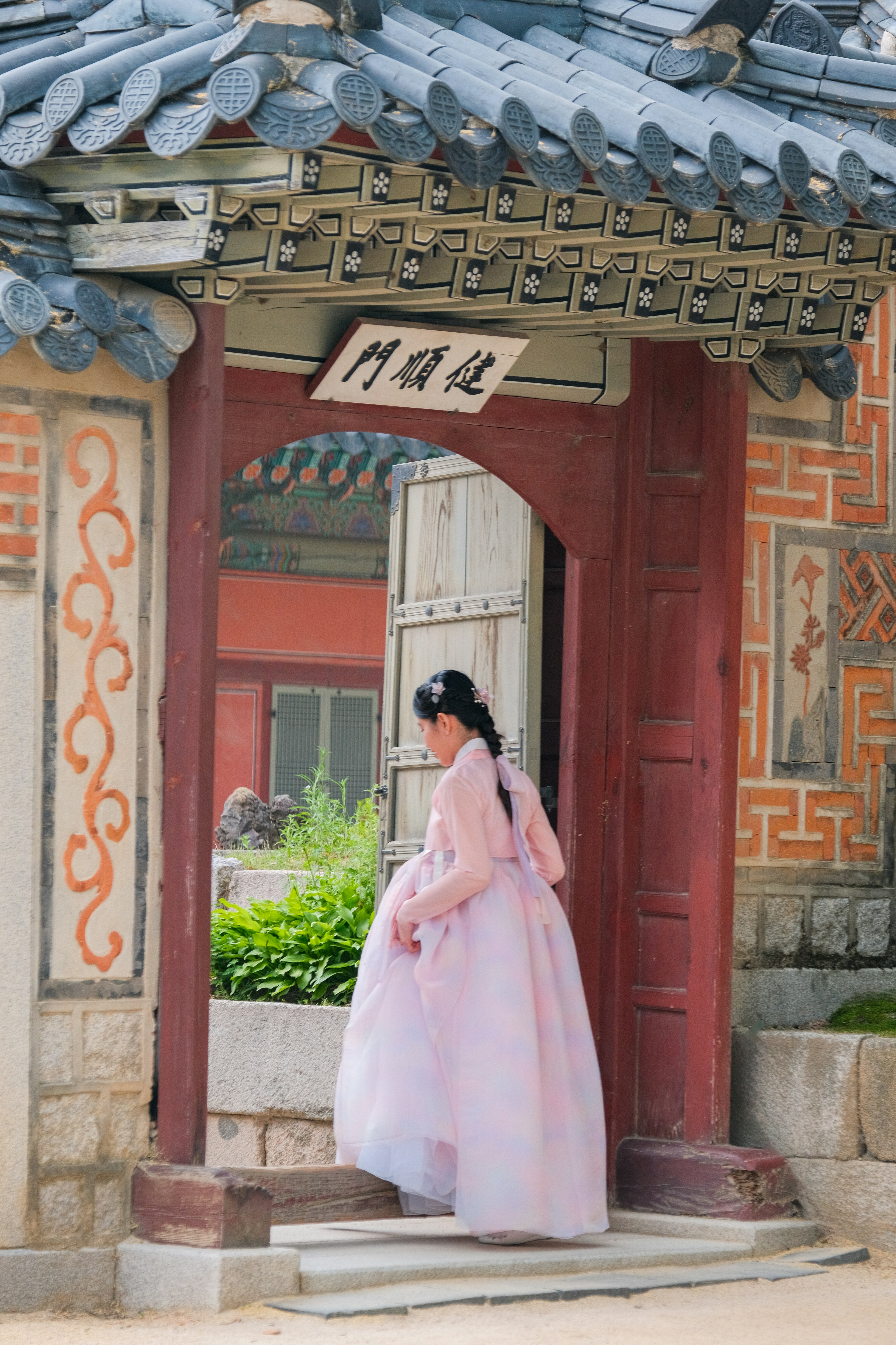 Pastel Hanbok Through a Carved Gate: A Quiet Moment in a Historic Courtyard