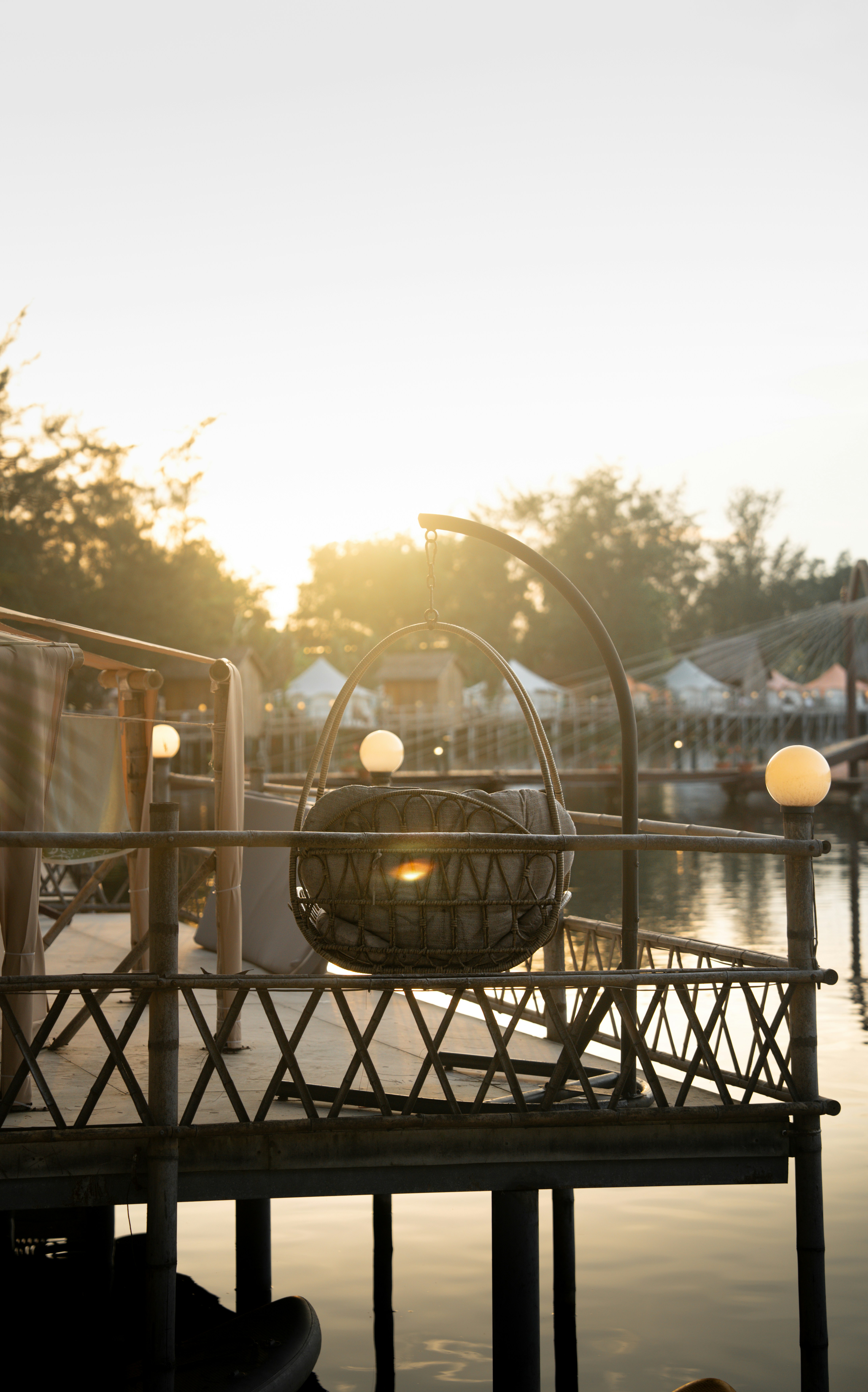 Golden Hour at the Dock: A Wicker Hanging Chair Framed by Lanterns