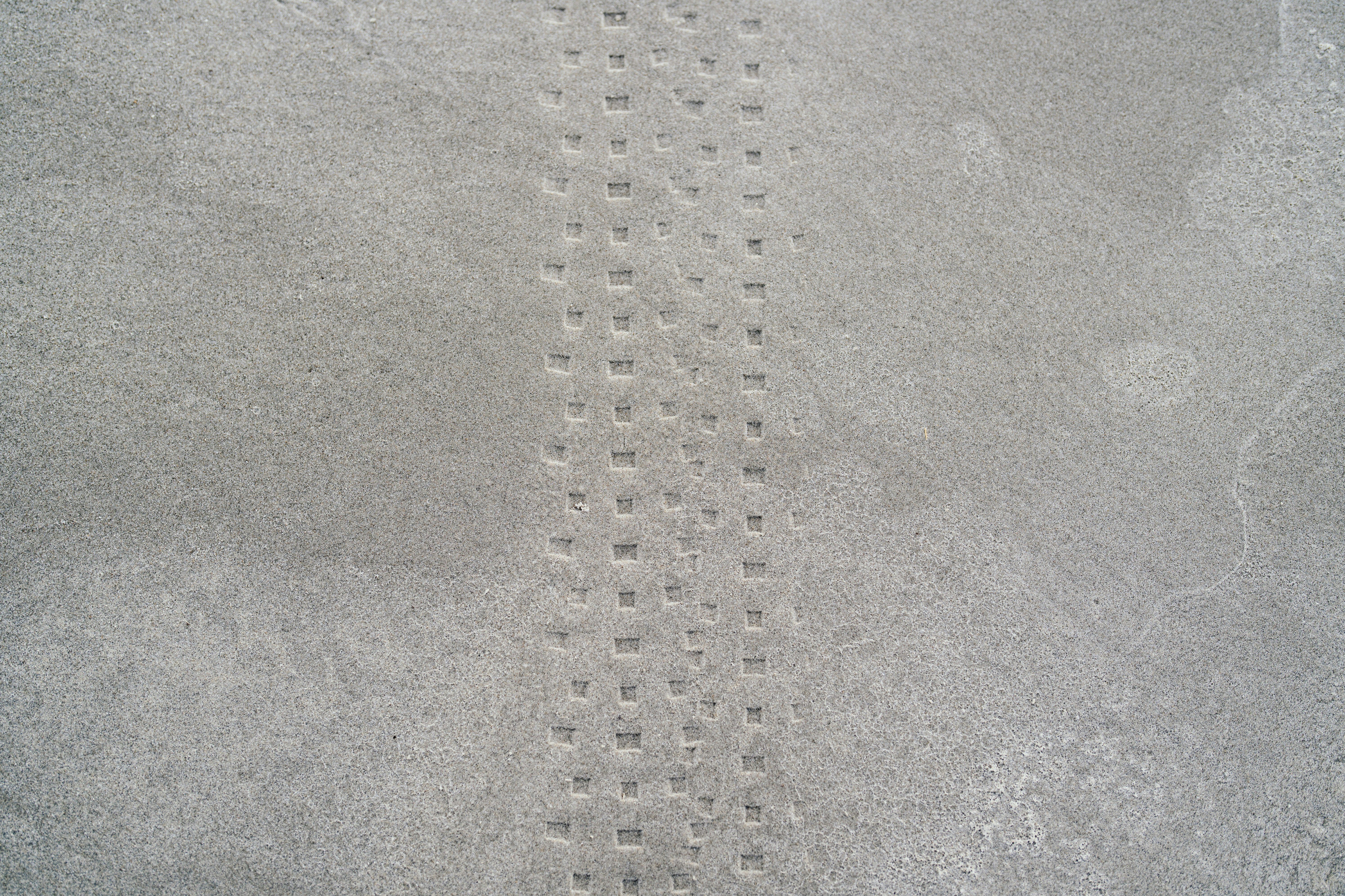 Strange pattern in the sand at the beach of Schiermonnikoog | Tire tracks are imprinted on a concrete surface.