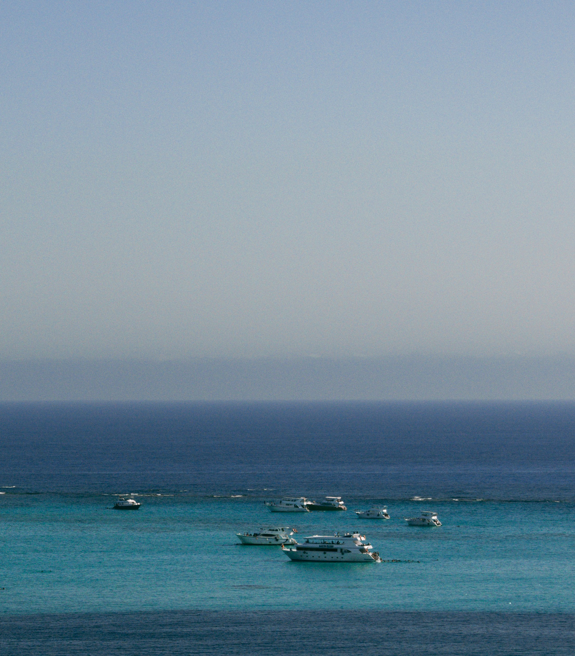 Boats are anchored in a beautiful, blue ocean. photo – Free Wallpaper ...