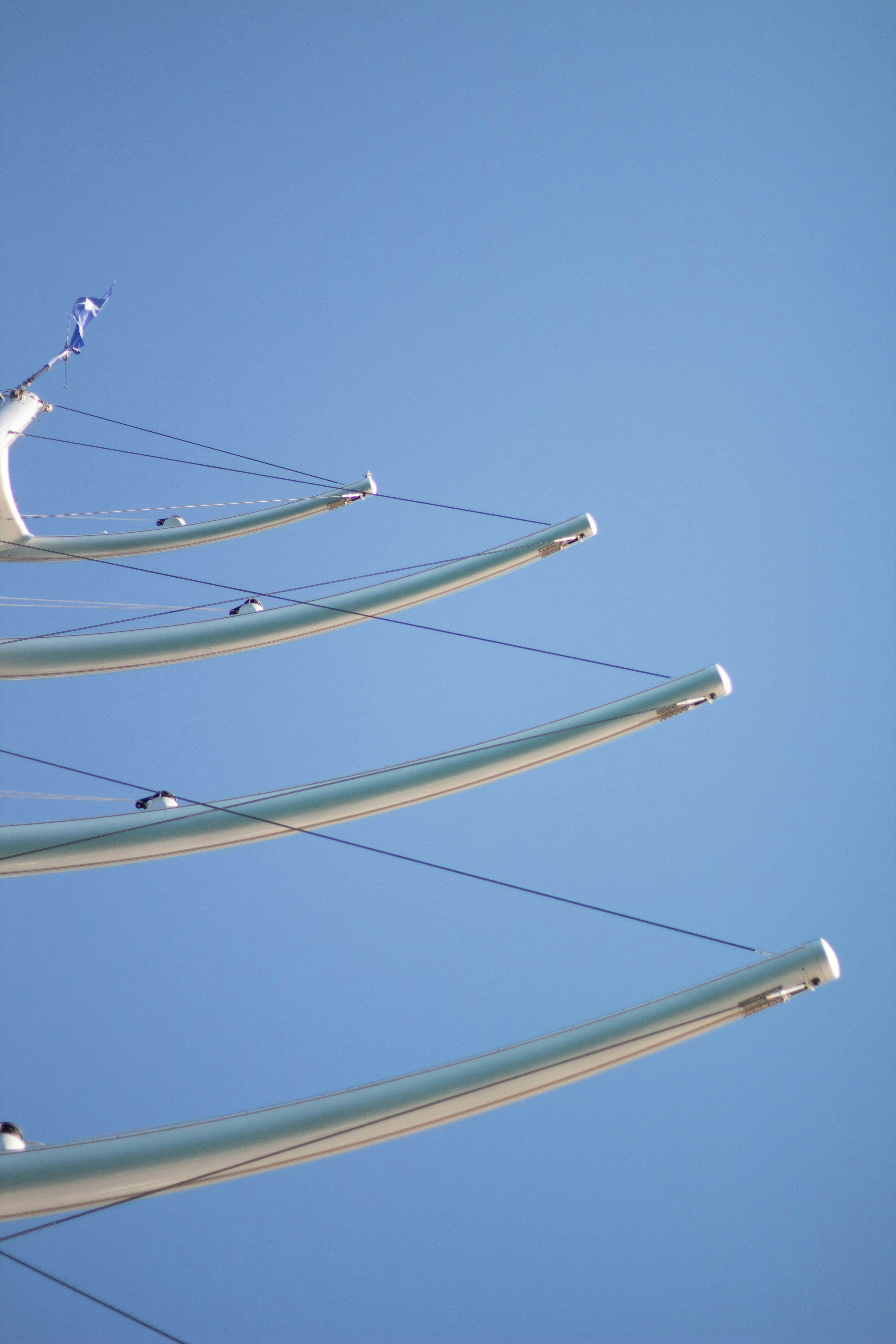 Three elegantly curved masts stretch skyward, framed by a clear blue backdrop.