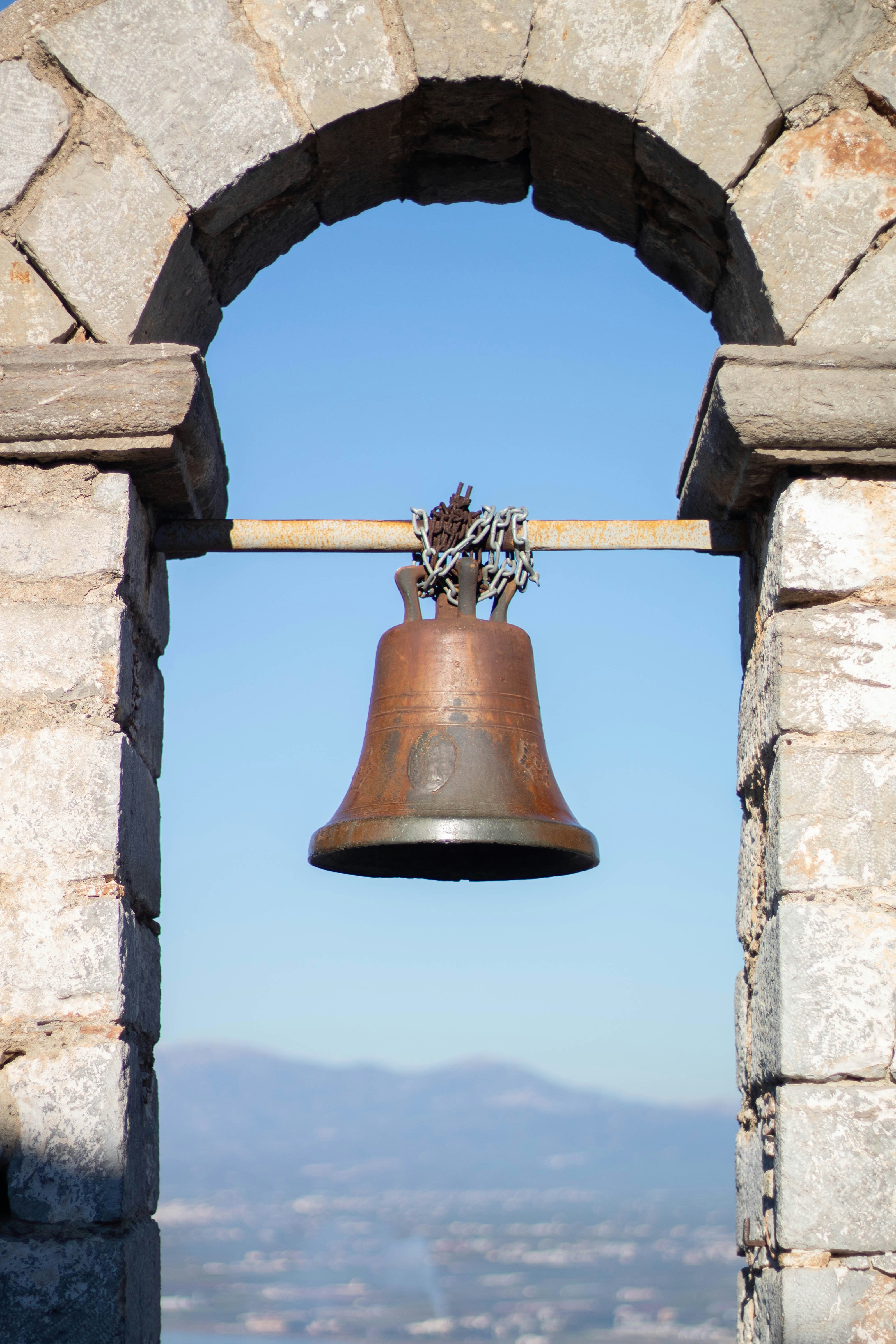 An old bell hangs inside a stone arch. photo – Free Bell Image on Unsplash