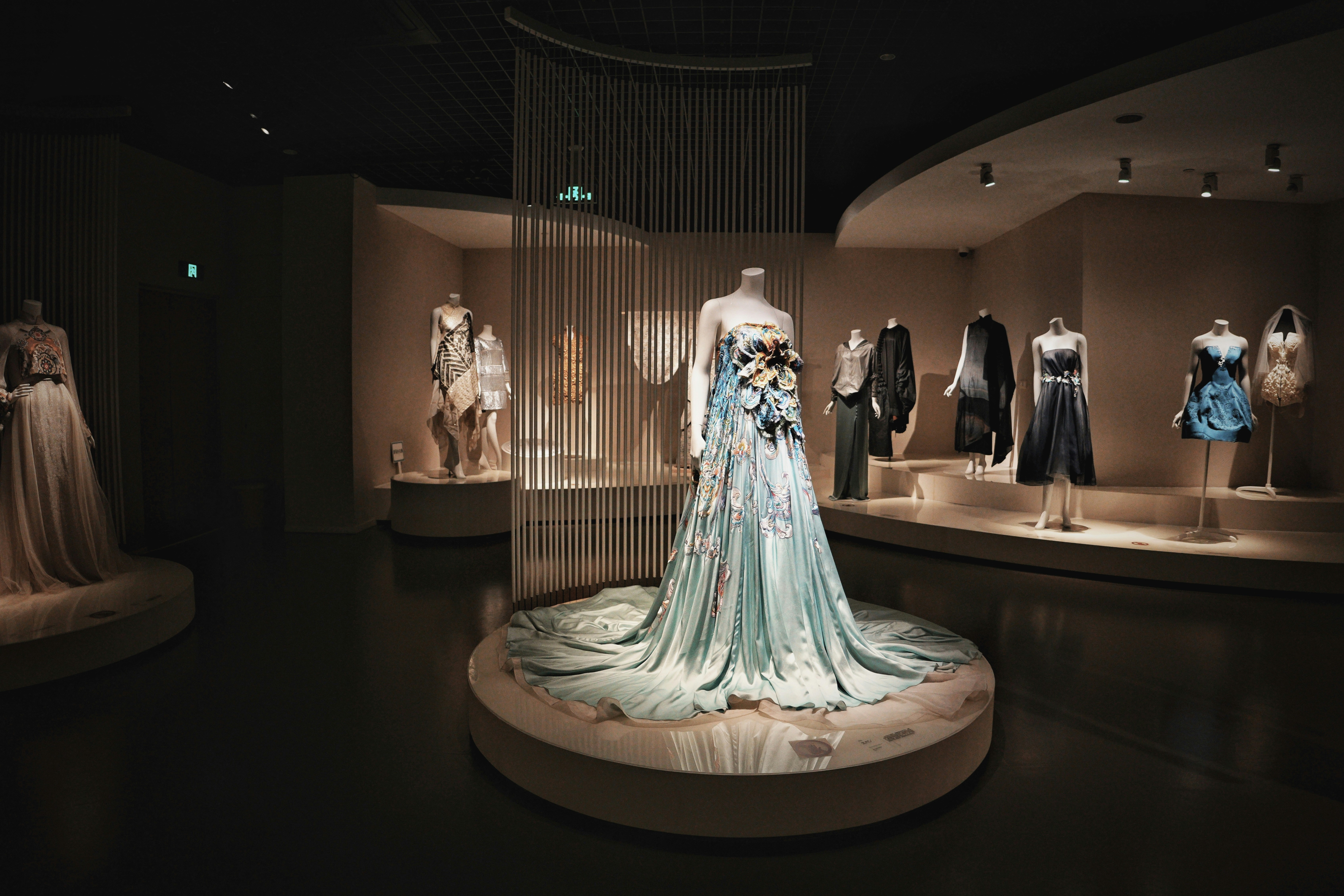 Teal Silk on a Circular Pedestal: Evening Gown Centerpiece in a Quiet Fashion Gallery