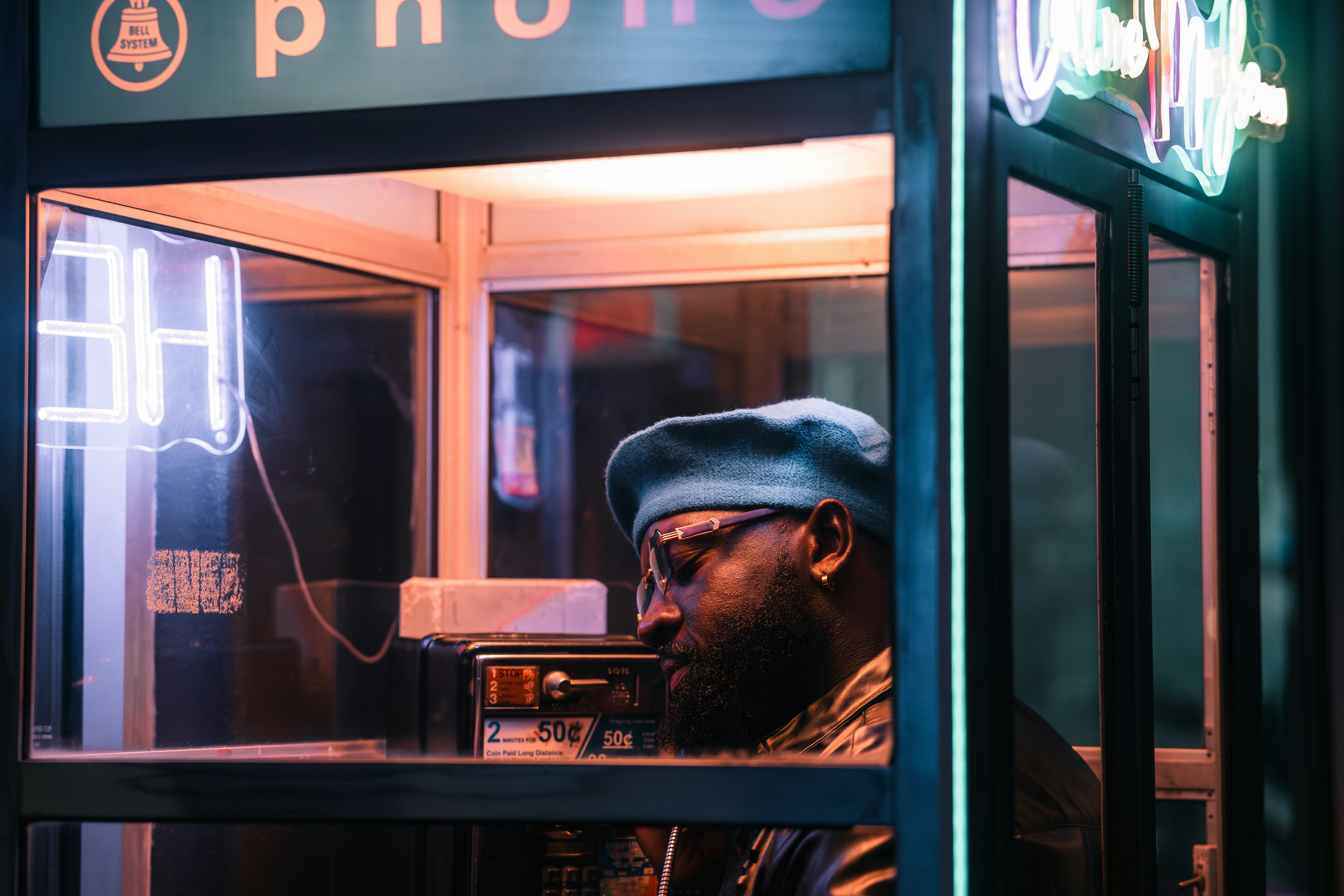 A man in a beret interacts with a vintage payphone, surrounded by vibrant neon lights reflecting a nostalgic urban atmosphere.
