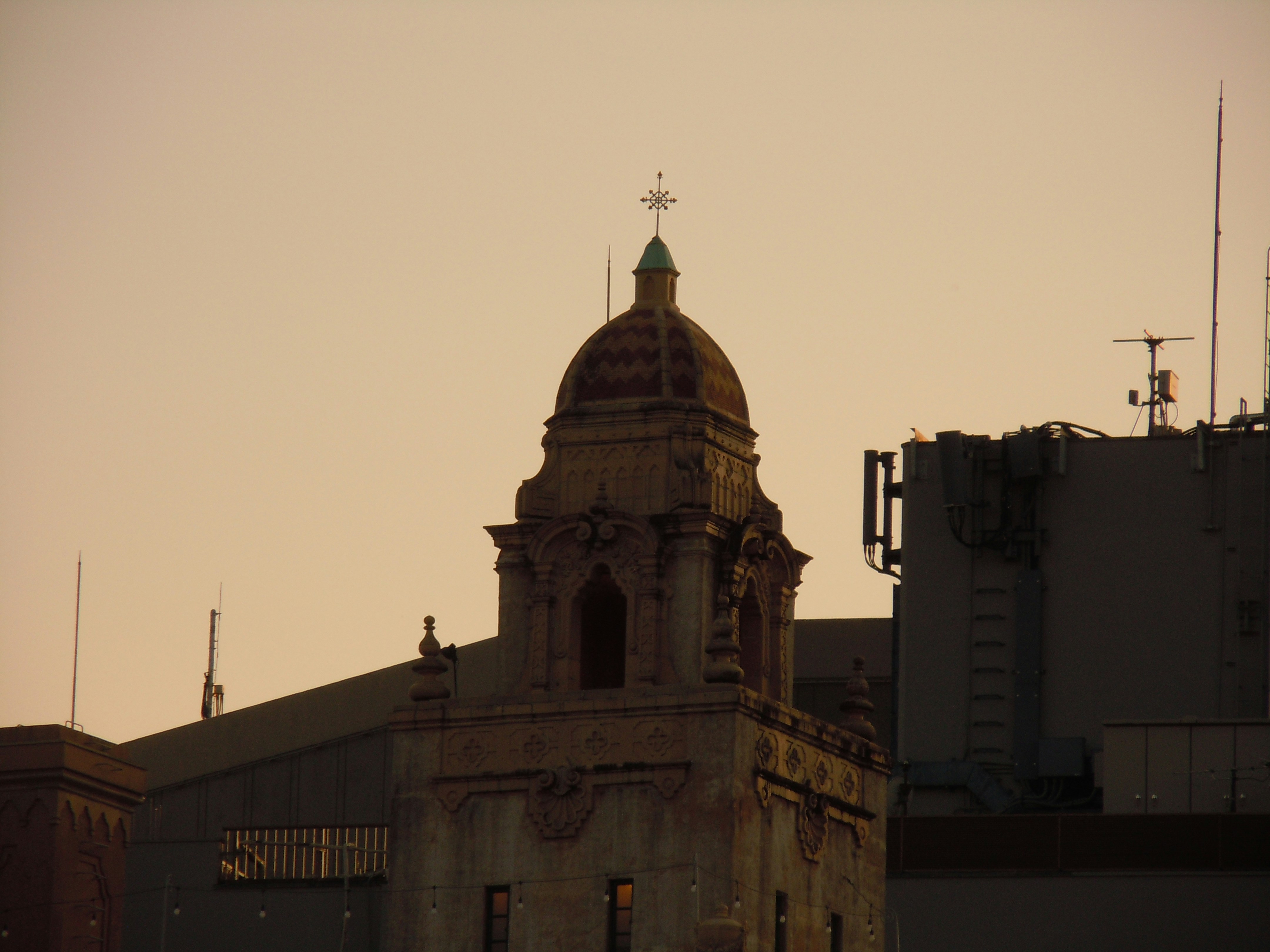 Historic building silhouette against a soft twilight sky, showcasing intricate architectural details and a prominent dome.