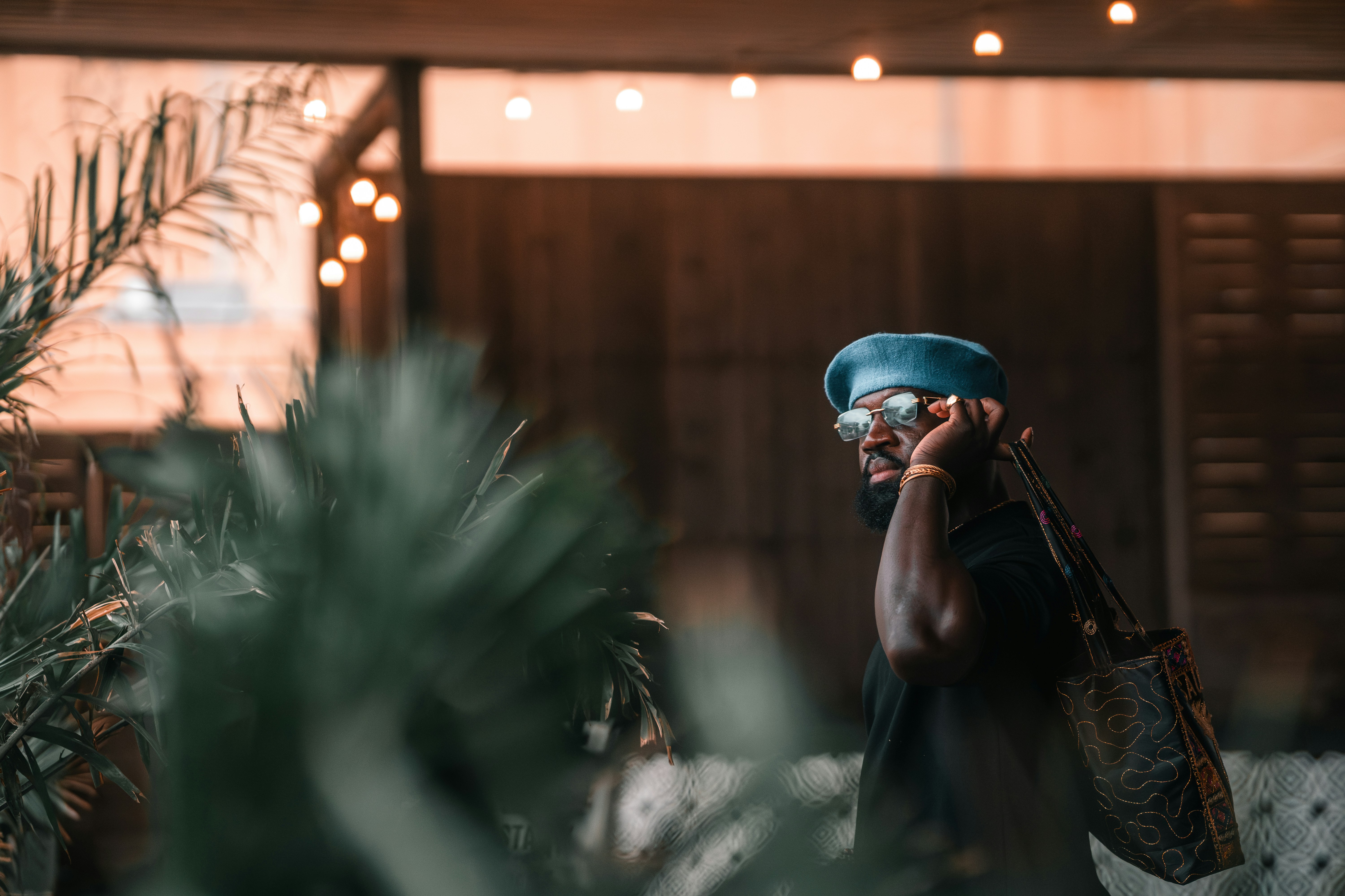 Evening Call Beneath Neon Warmth: A Man in a Teal Cap
