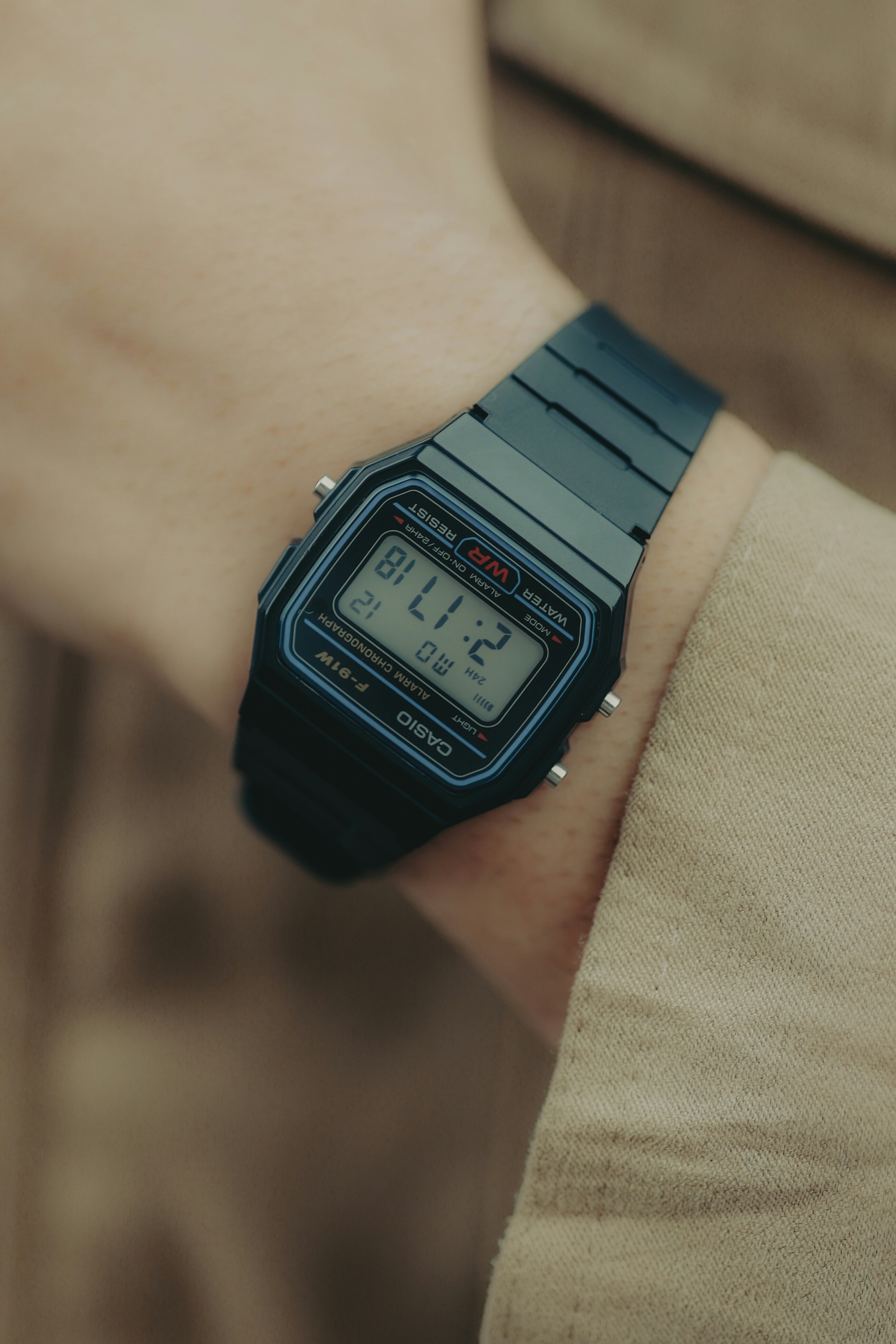 A wrist displays a black casio digital watch.