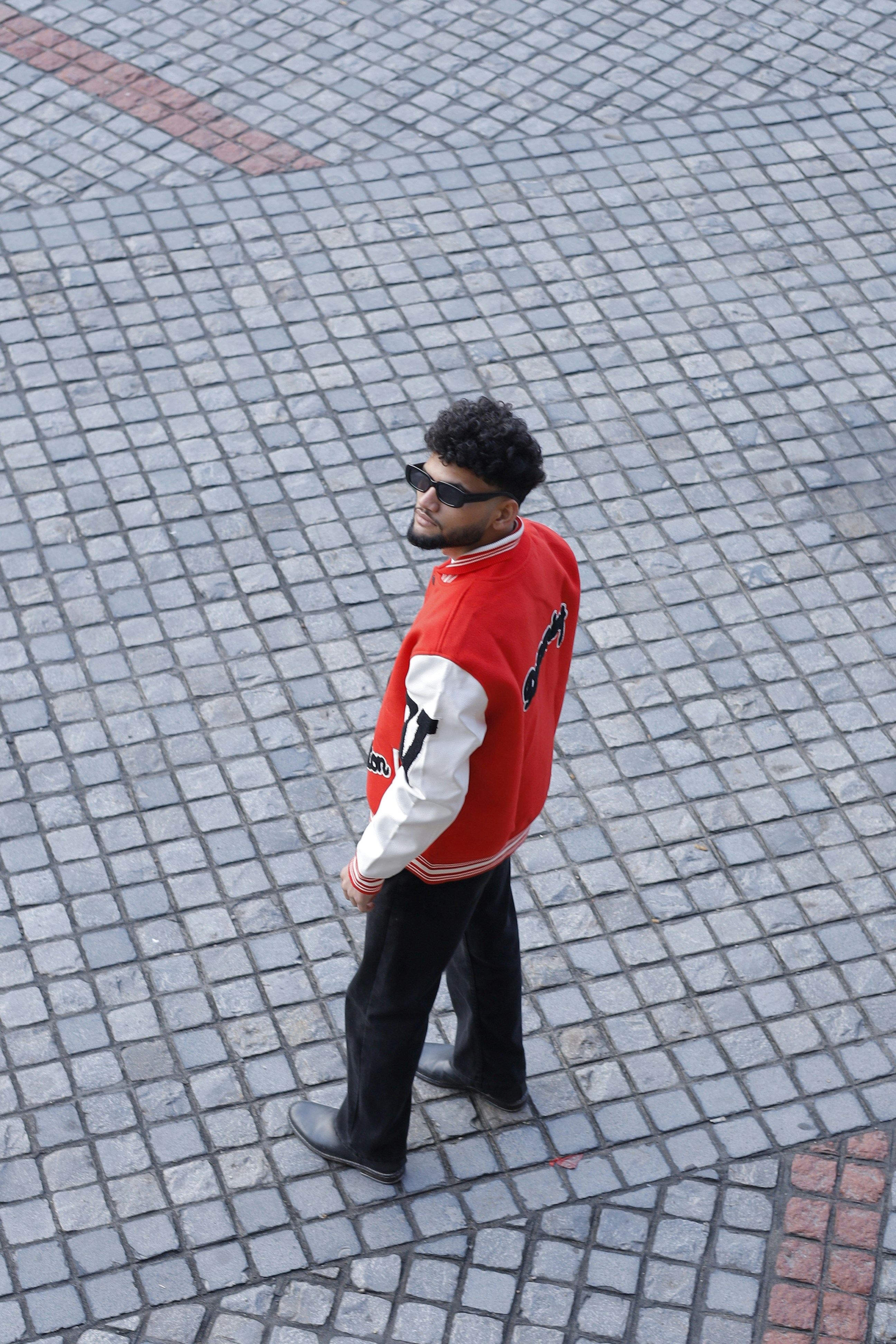Man poses stylishly on a cobblestone path.
