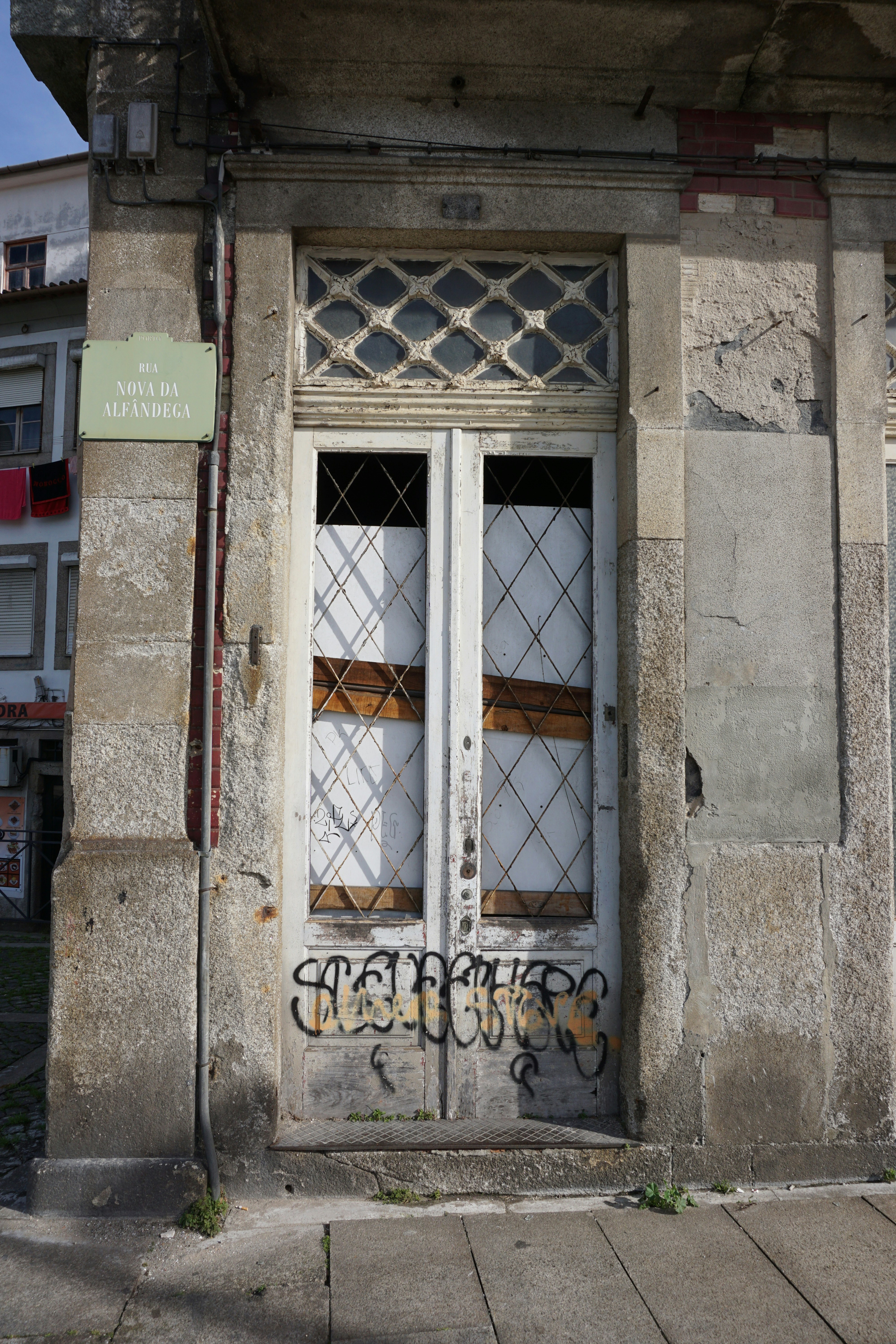 Stone Portal: Diamond-Grilled Doorway Framed by Graffiti and Weathered Stone