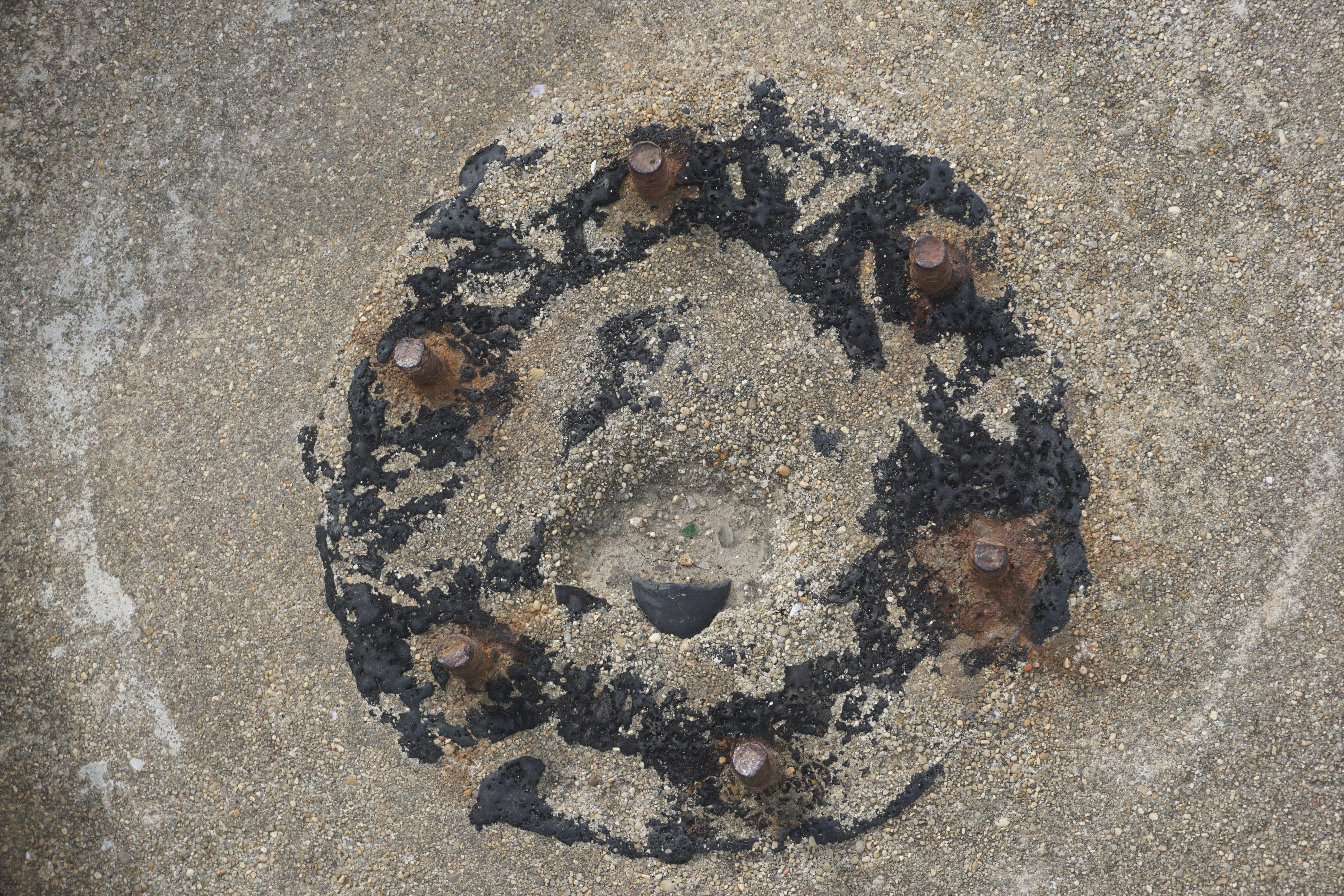 Timeworn Ring: A Weathered Bolt Circle Embedded in Cracked Concrete