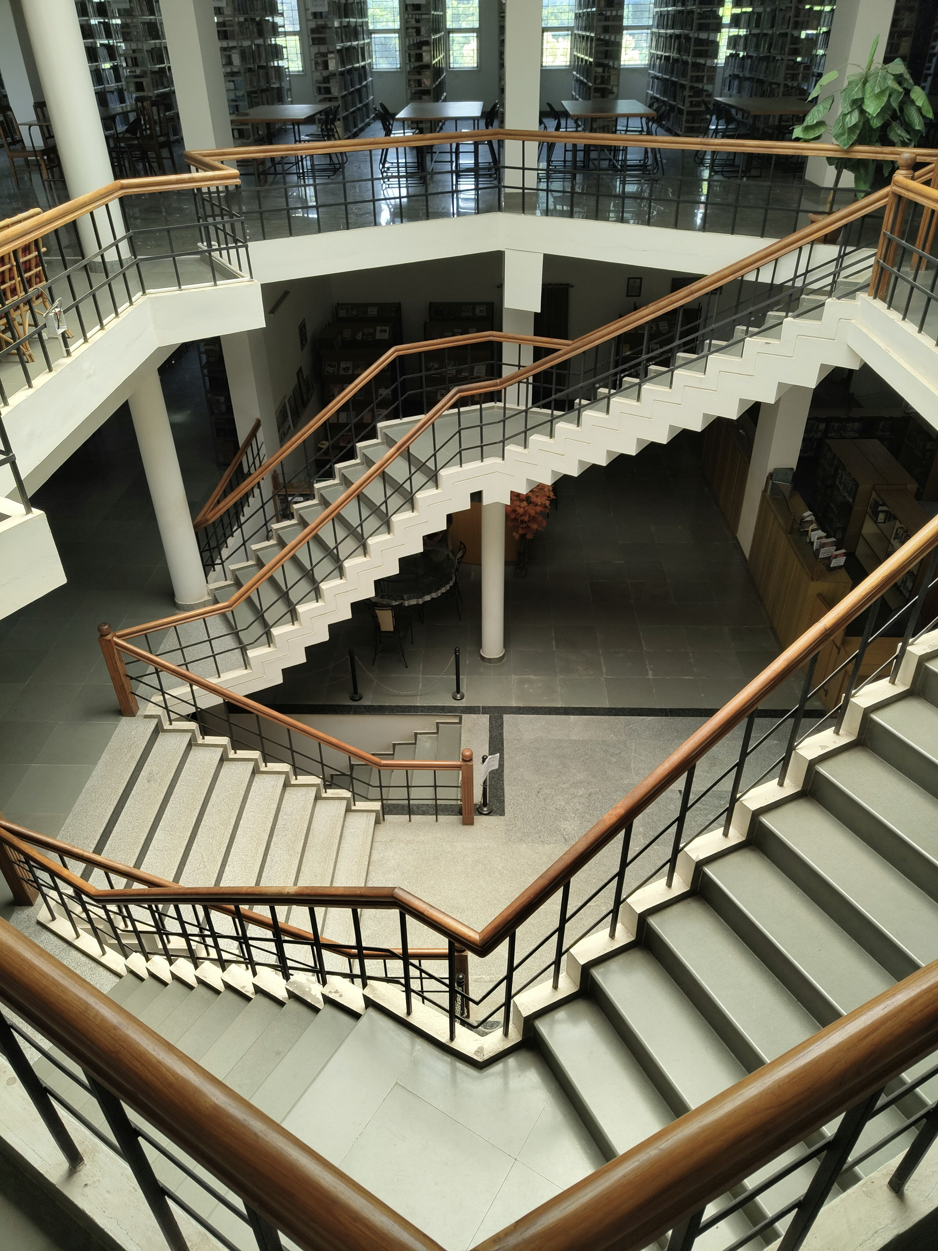 Staircases spiral downward in a bright library space.