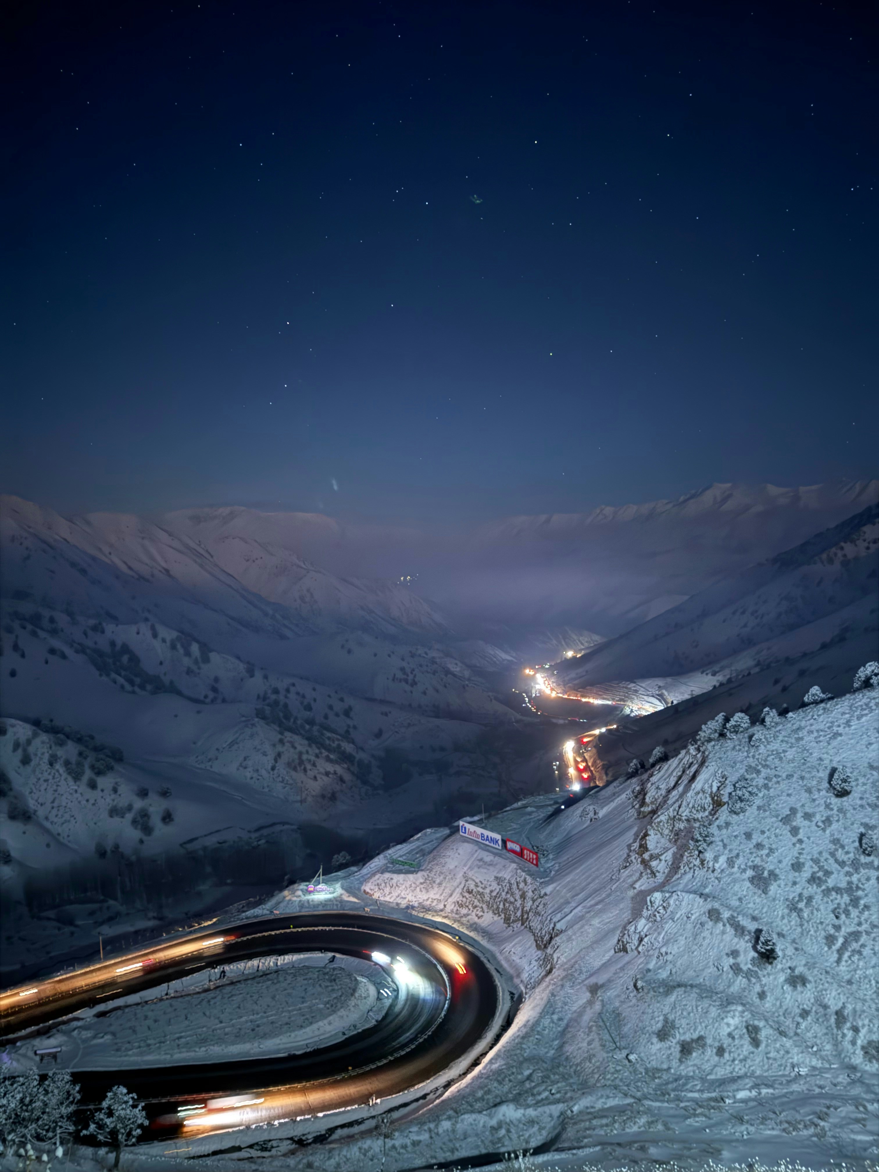 A winding road through snowy mountains at night. photo – Free Road ...