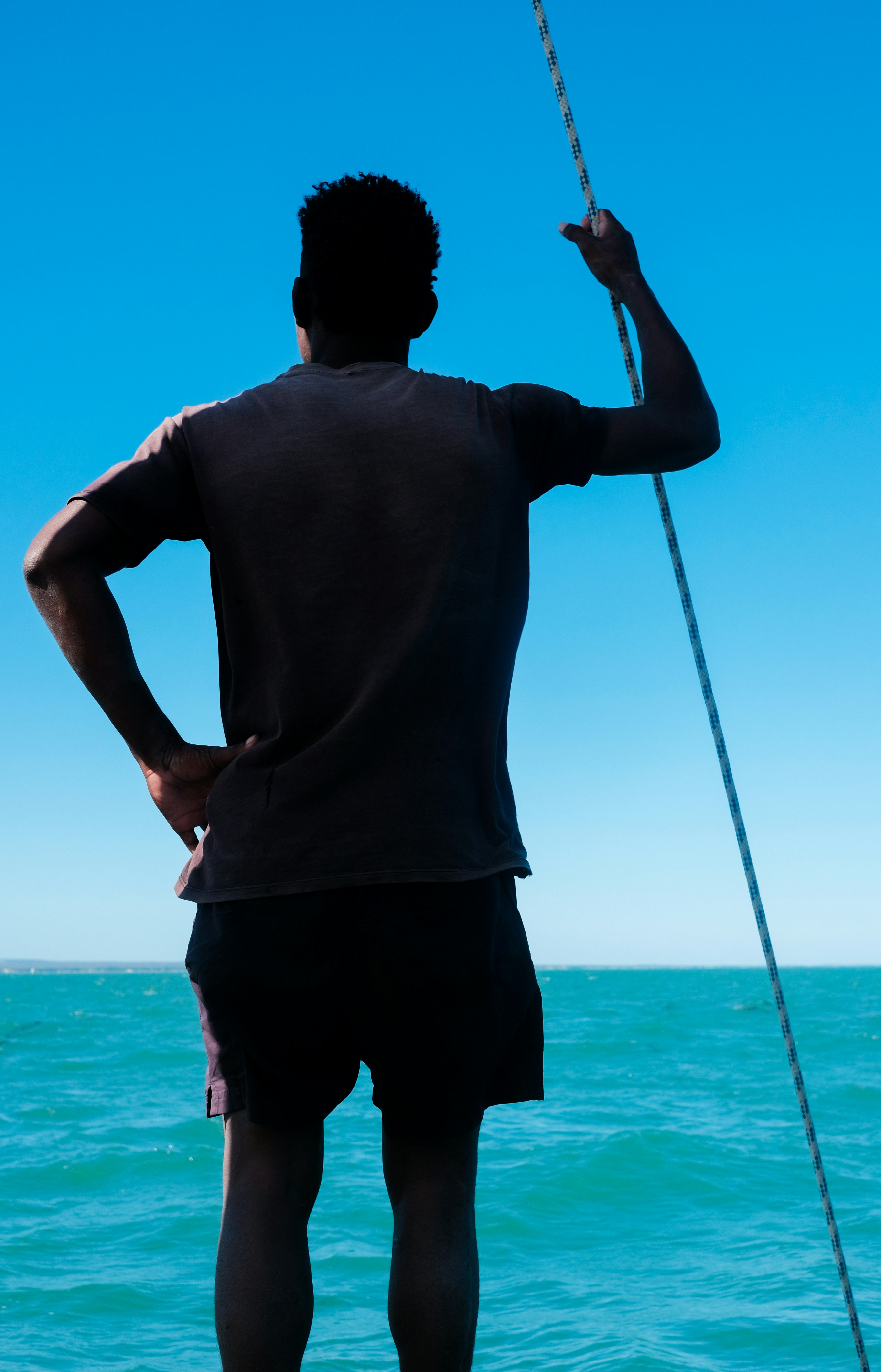 Backlit by Sky: A Lone Figure Climb near the Sea