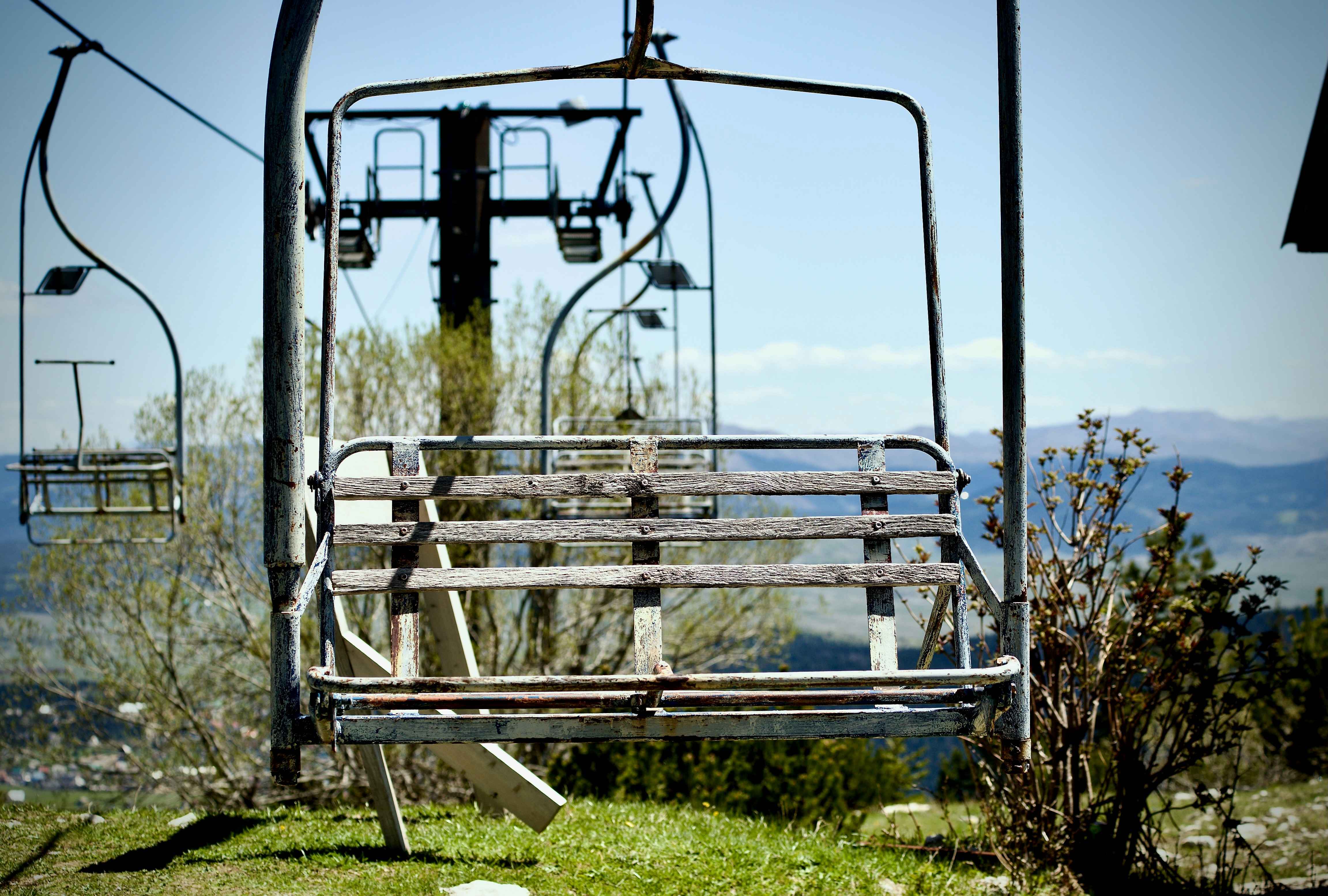 Weathered chairlift suspended against a backdrop of distant mountains, hinting at past winter escapades.