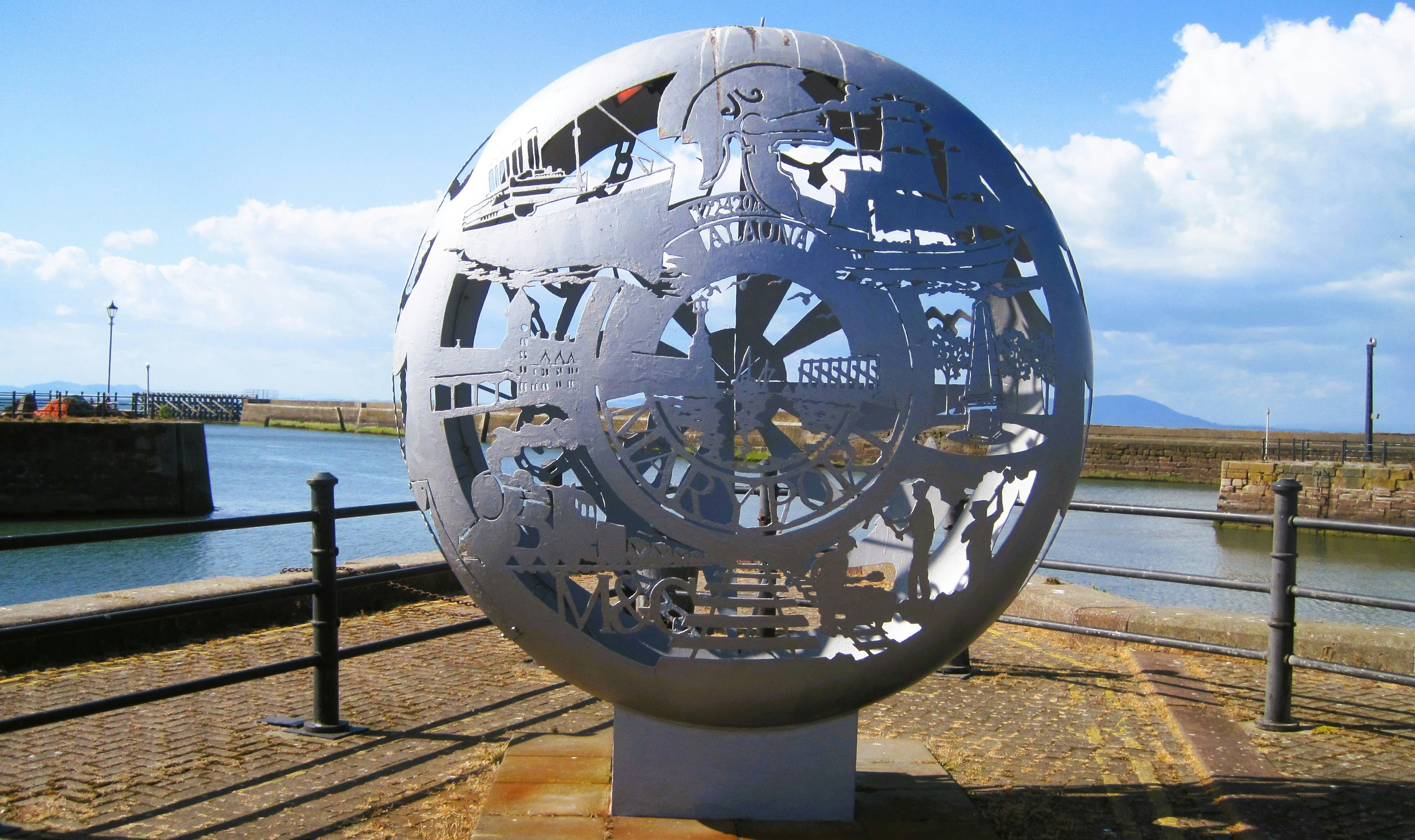 Harbor Globe: A Sunlit Perforated Sphere at the Water's Edge