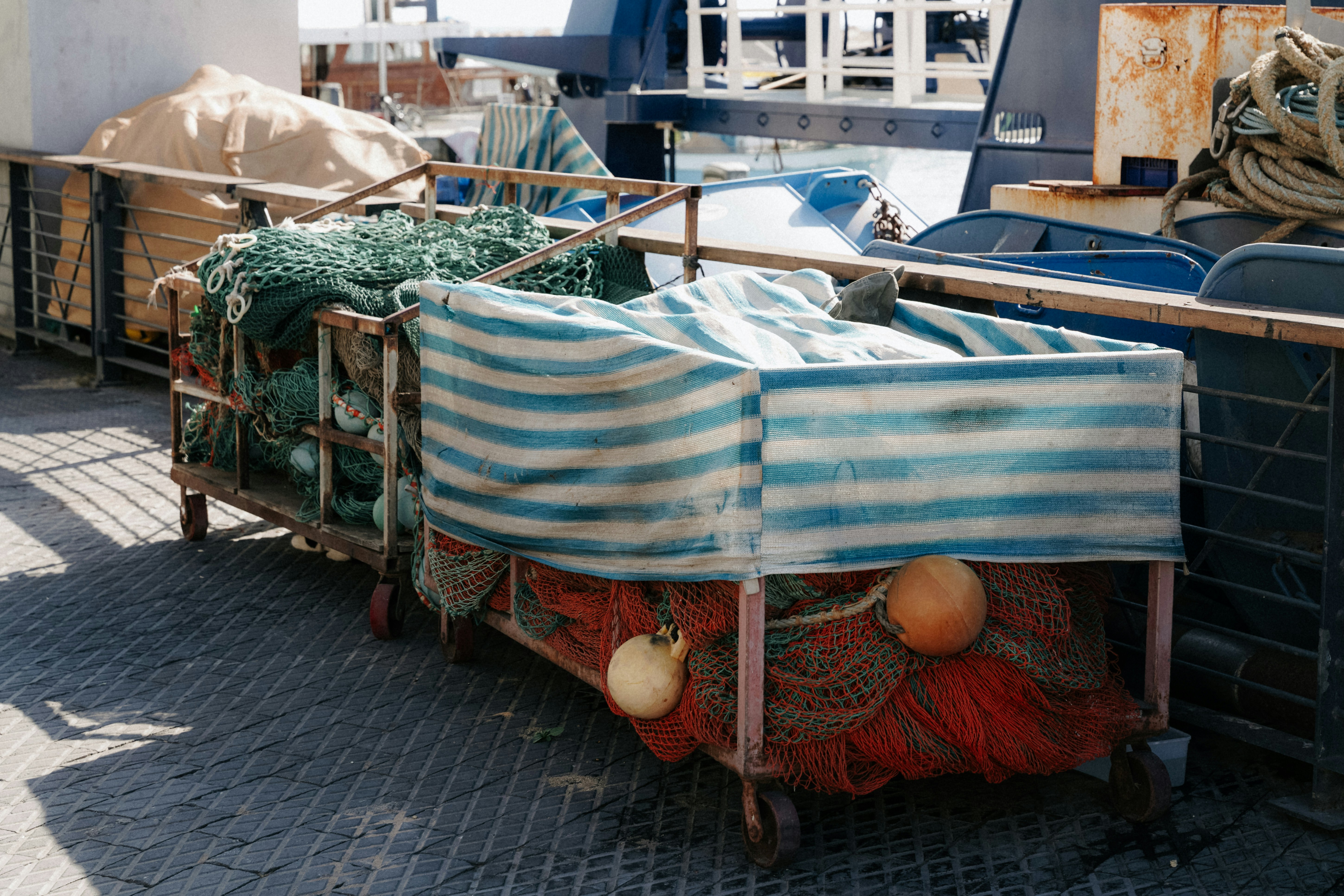 Colorful fishing nets and buoys covered with striped tarps at a harbor. The scene captures the essence of maritime life.