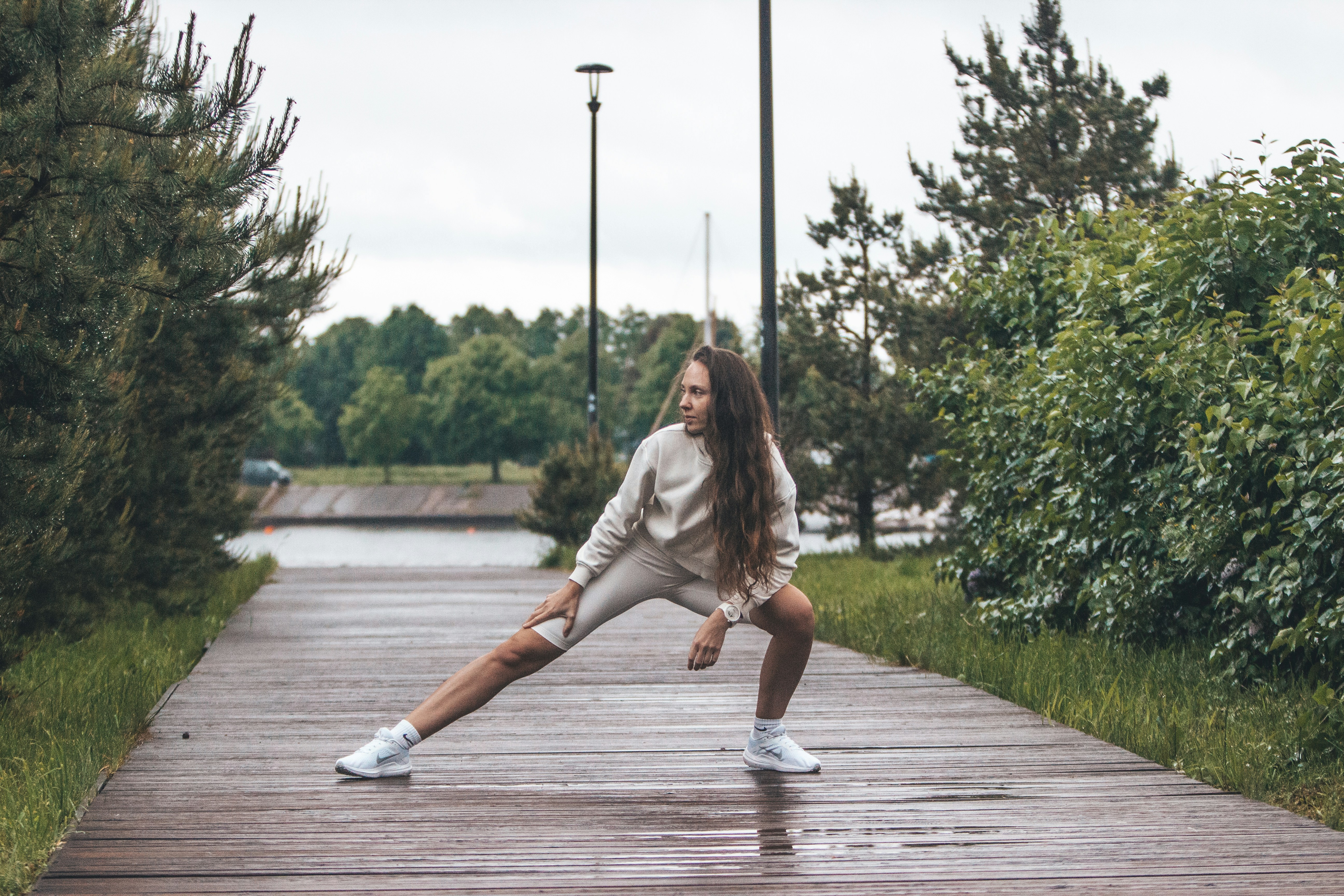 A dancer showcases a fluid pose on a wooden pathway surrounded by lush greenery, highlighting the harmony between movement and nature.