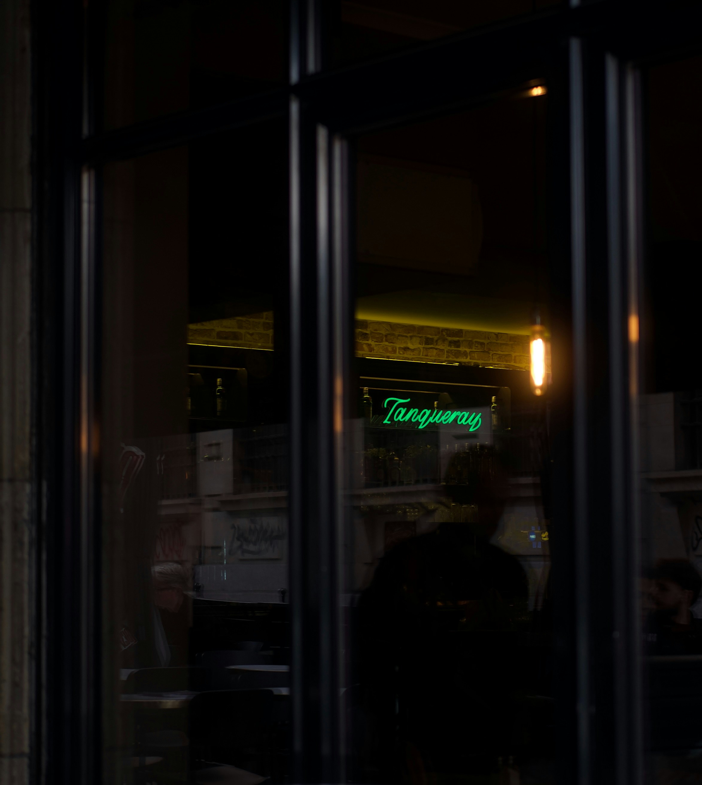 A neon sign glows inside a dark window.
