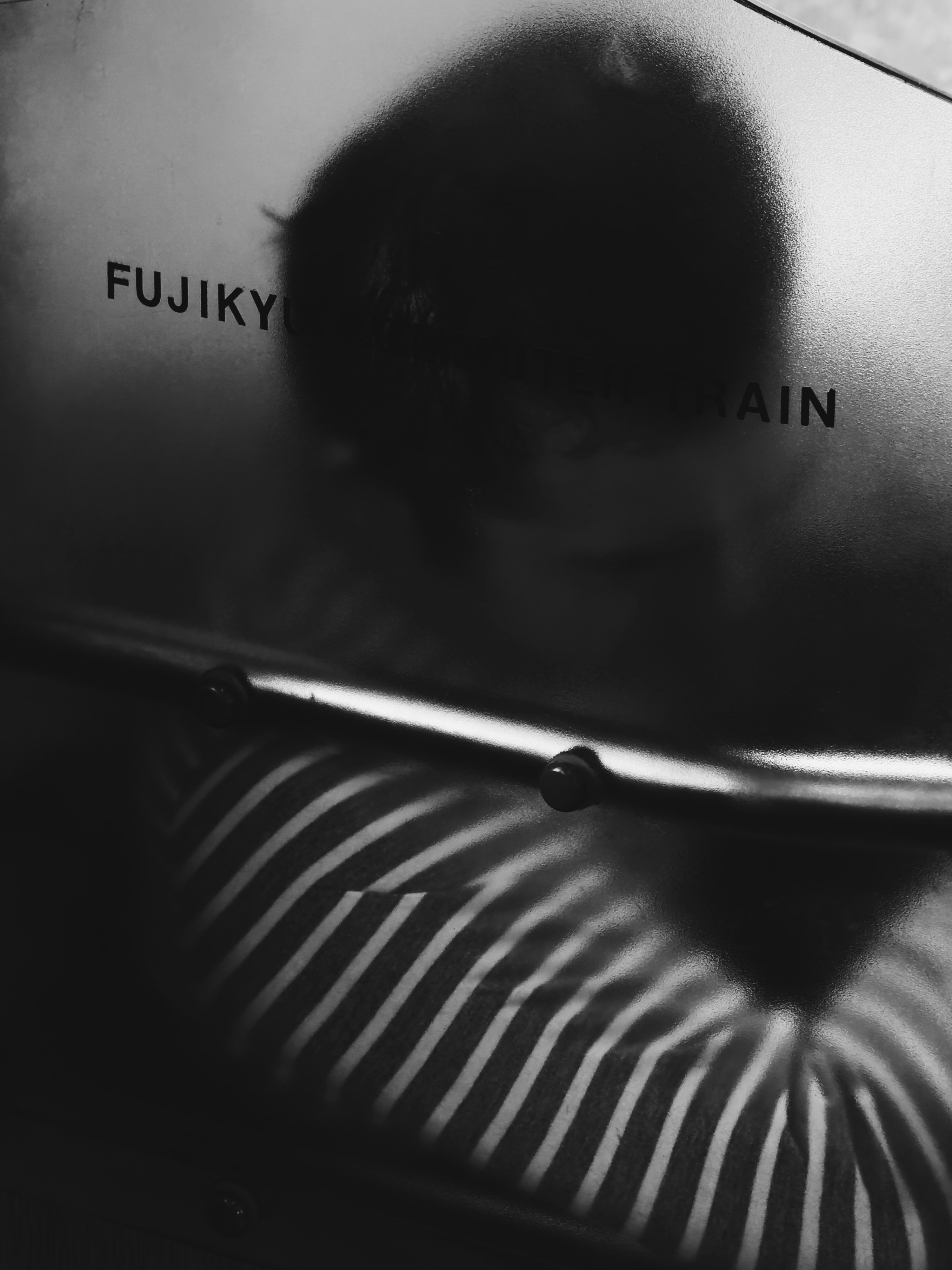 A blurred figure with arms crossed, partially obscured by fogged glass featuring the text 'FUJIKY'.