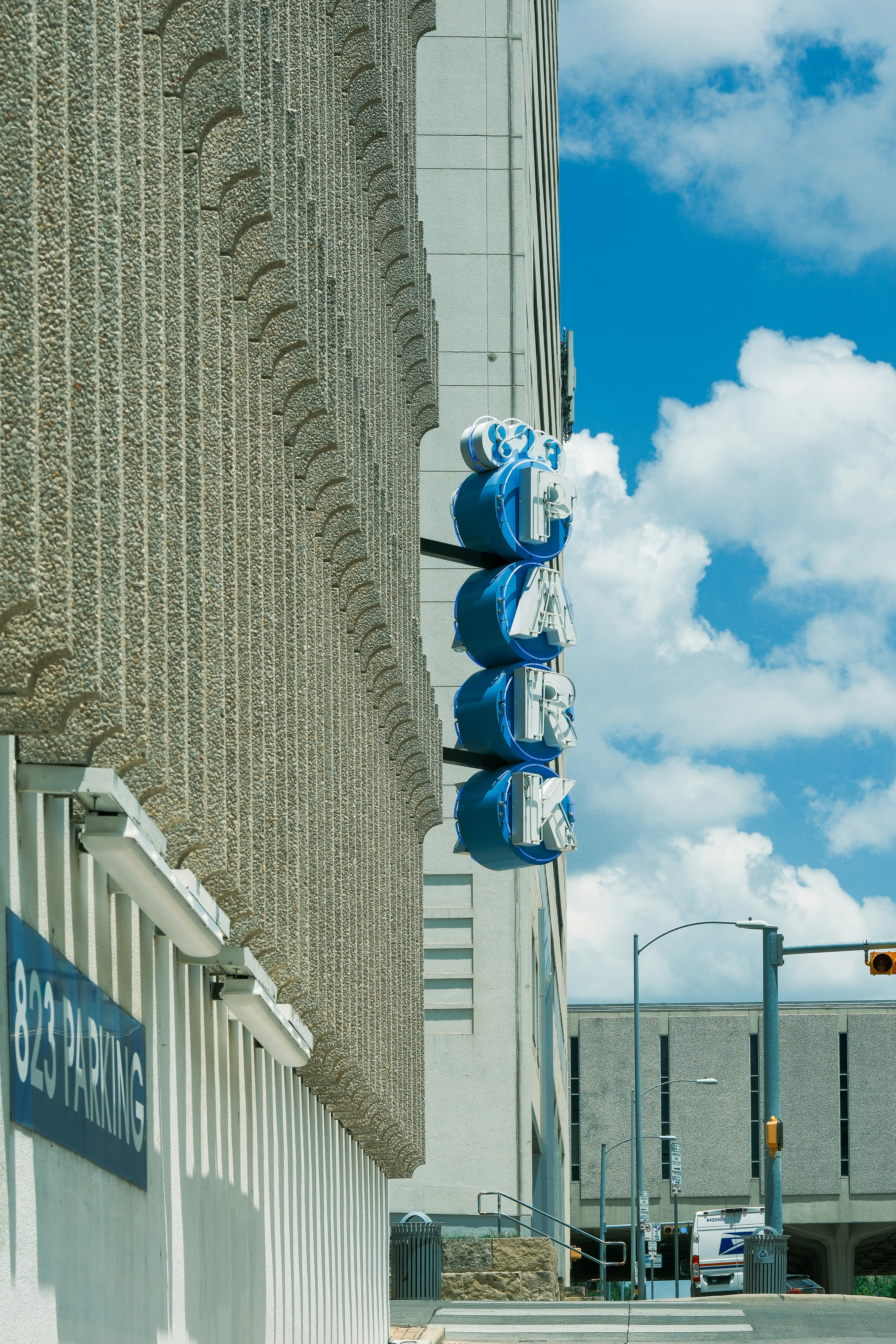 Blue Cylinders in Rhythm Along a Sunlit Concrete Facade