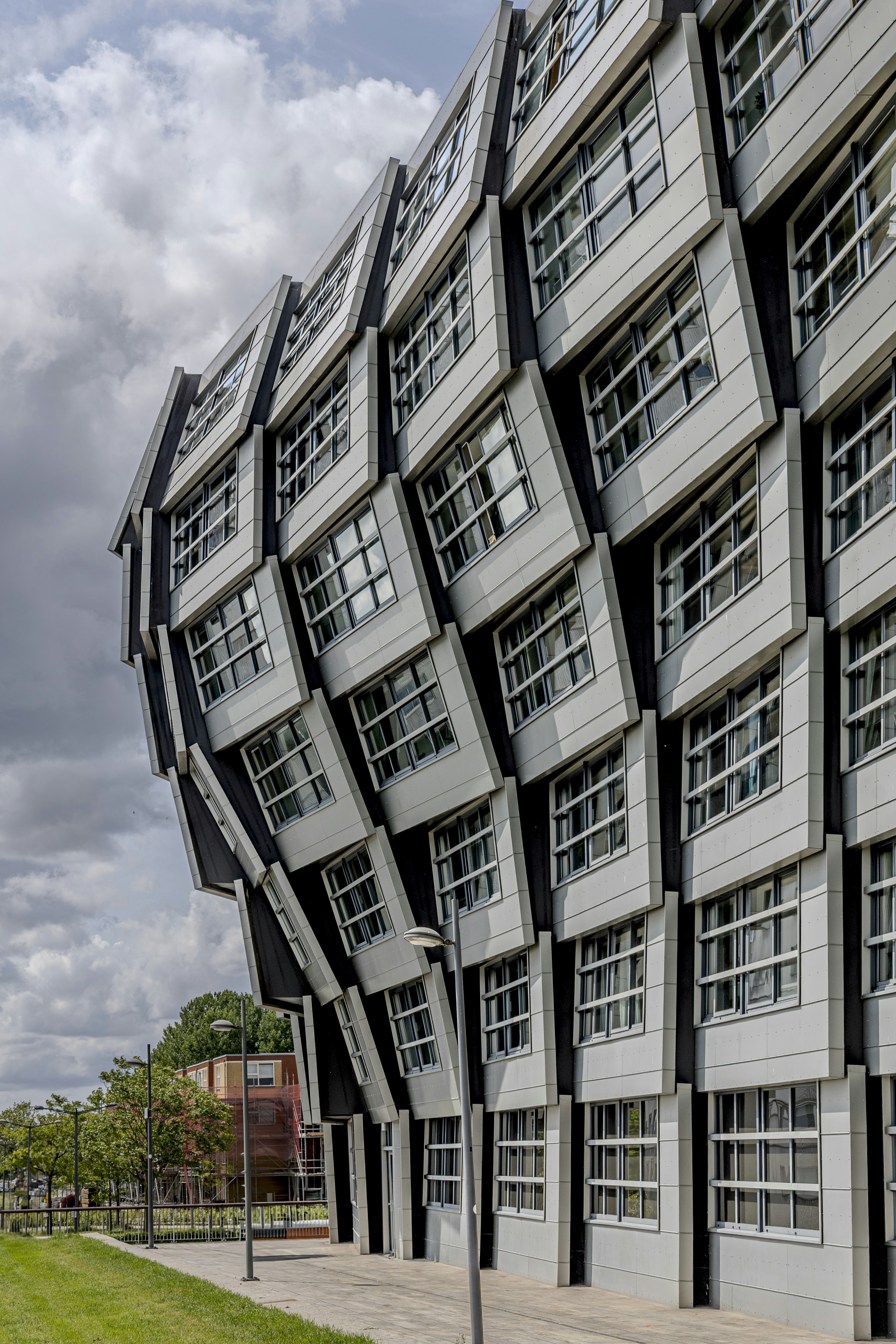 An HDR capture of “The Wave” on Koetsiersbaan in Almere, showcasing its dynamic, undulating façade under dramatic skies. | Modern building with an interesting, angular design.