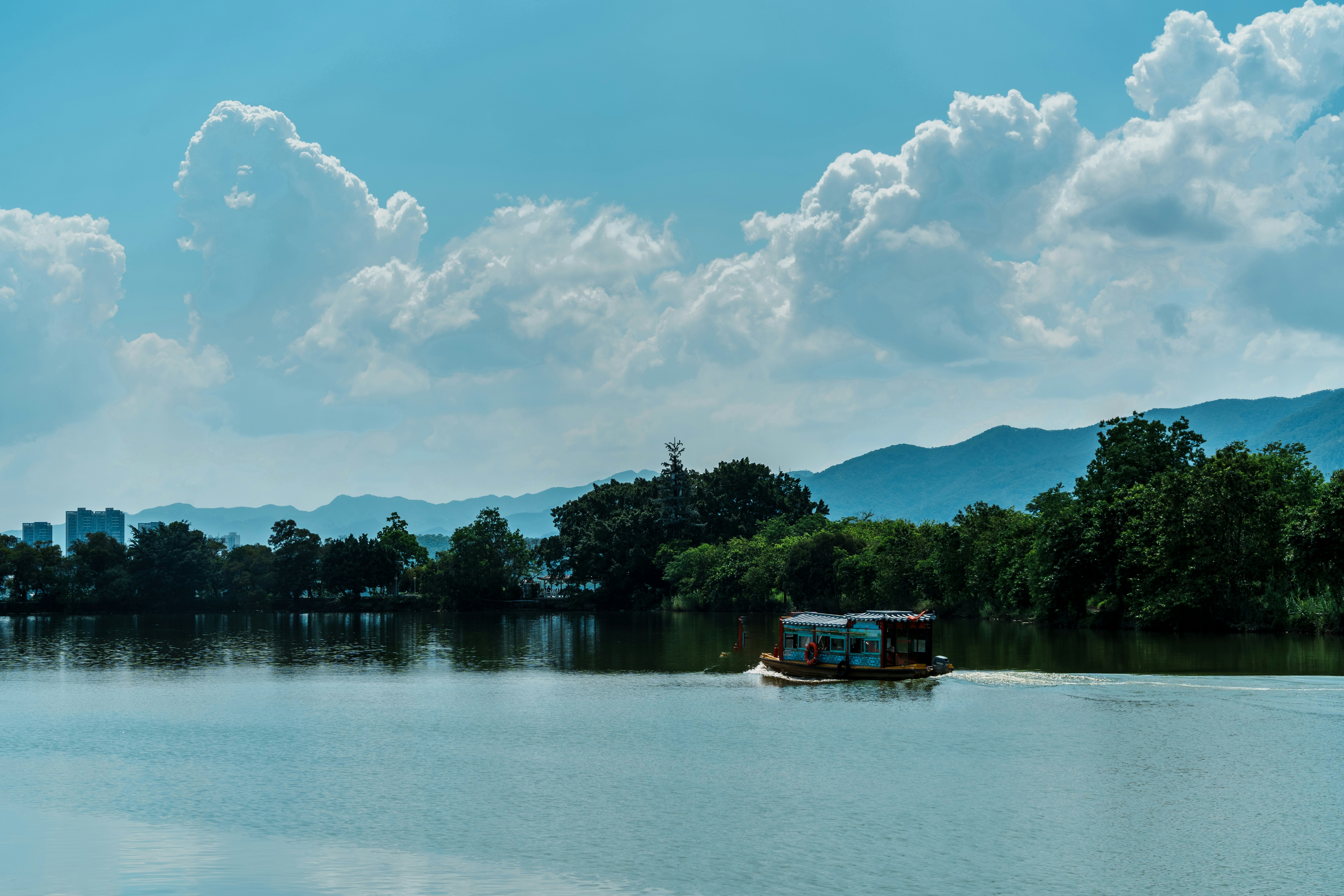 A boat floats on a calm lake under a cloudy sky.