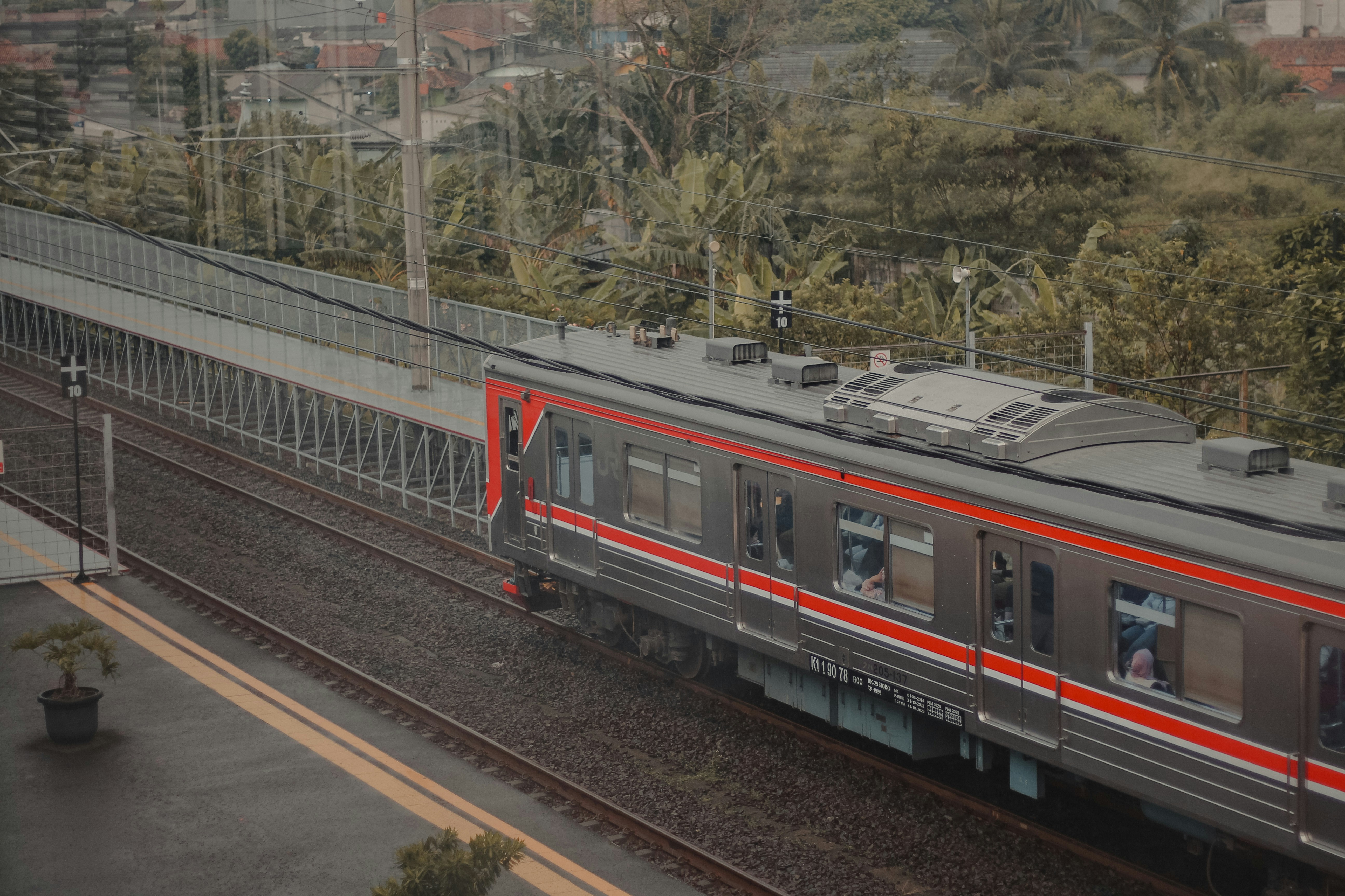 Midday Glide: Red-Trimmed Commuter Train Rounds a Quiet Station