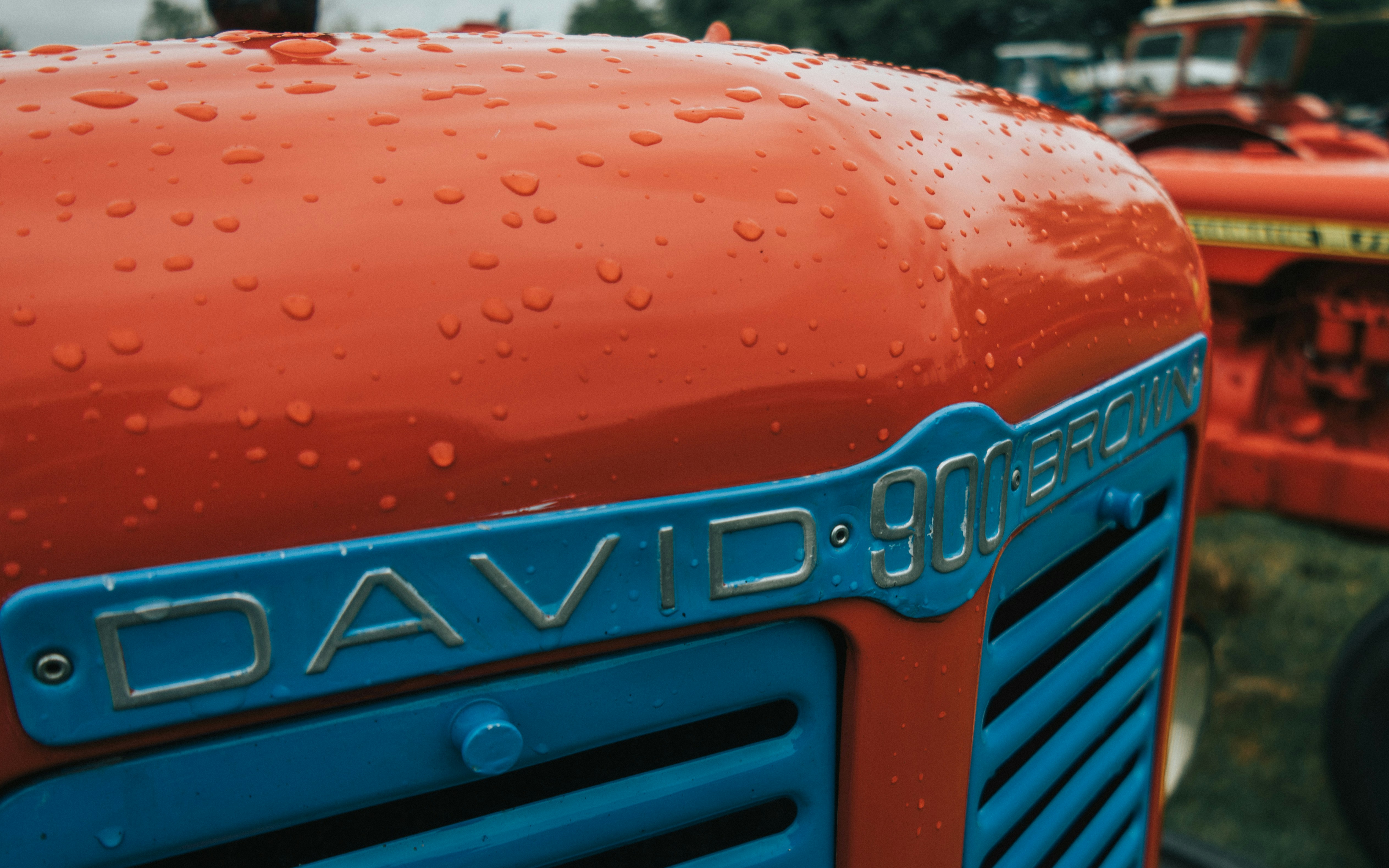 Close-up of a vintage David Brown 900 tractor adorned with raindrops, showcasing its classic design and vibrant colors.
