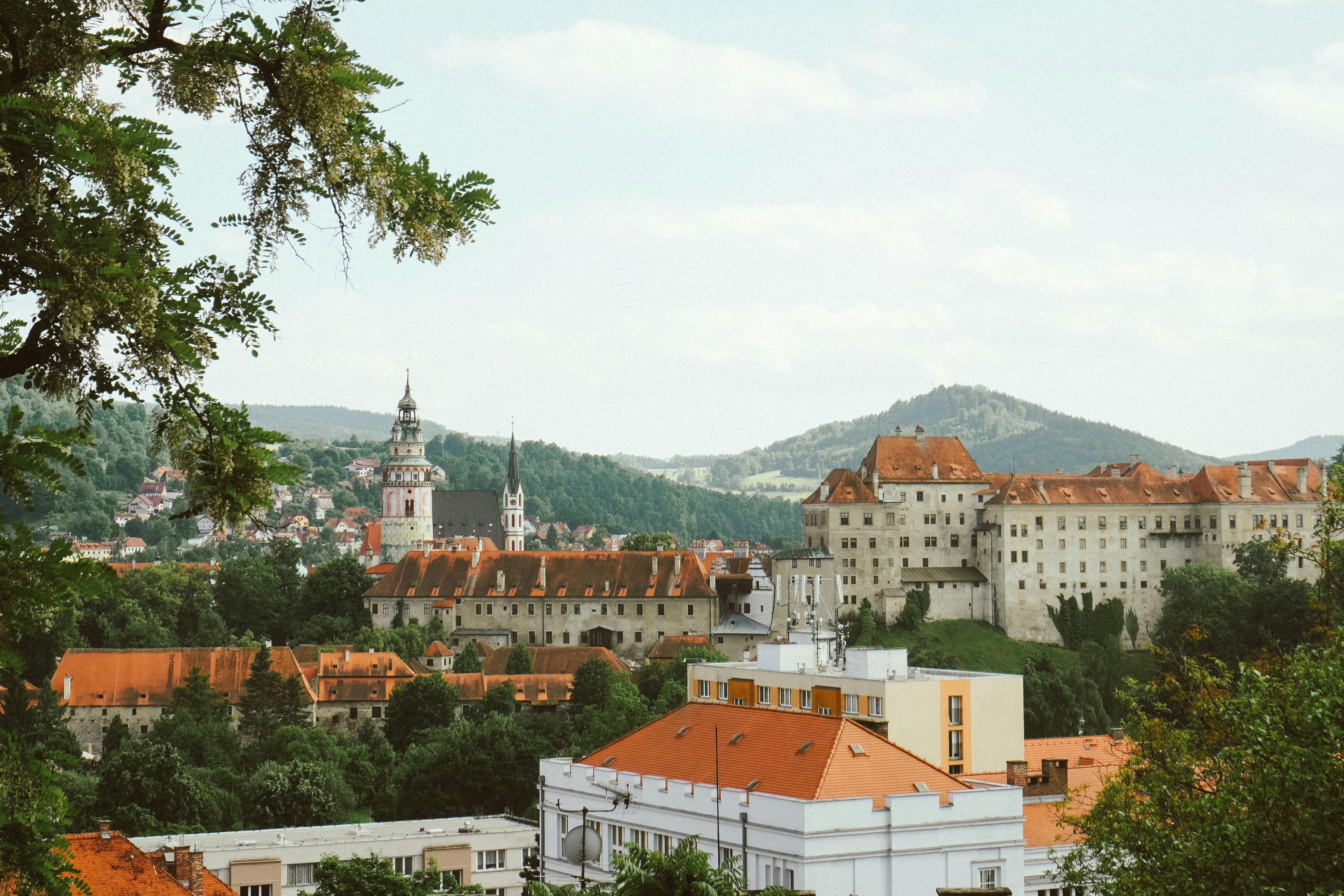 Historic castle and towers nestled in a verdant valley, showcasing medieval architecture against a backdrop of rolling hills.