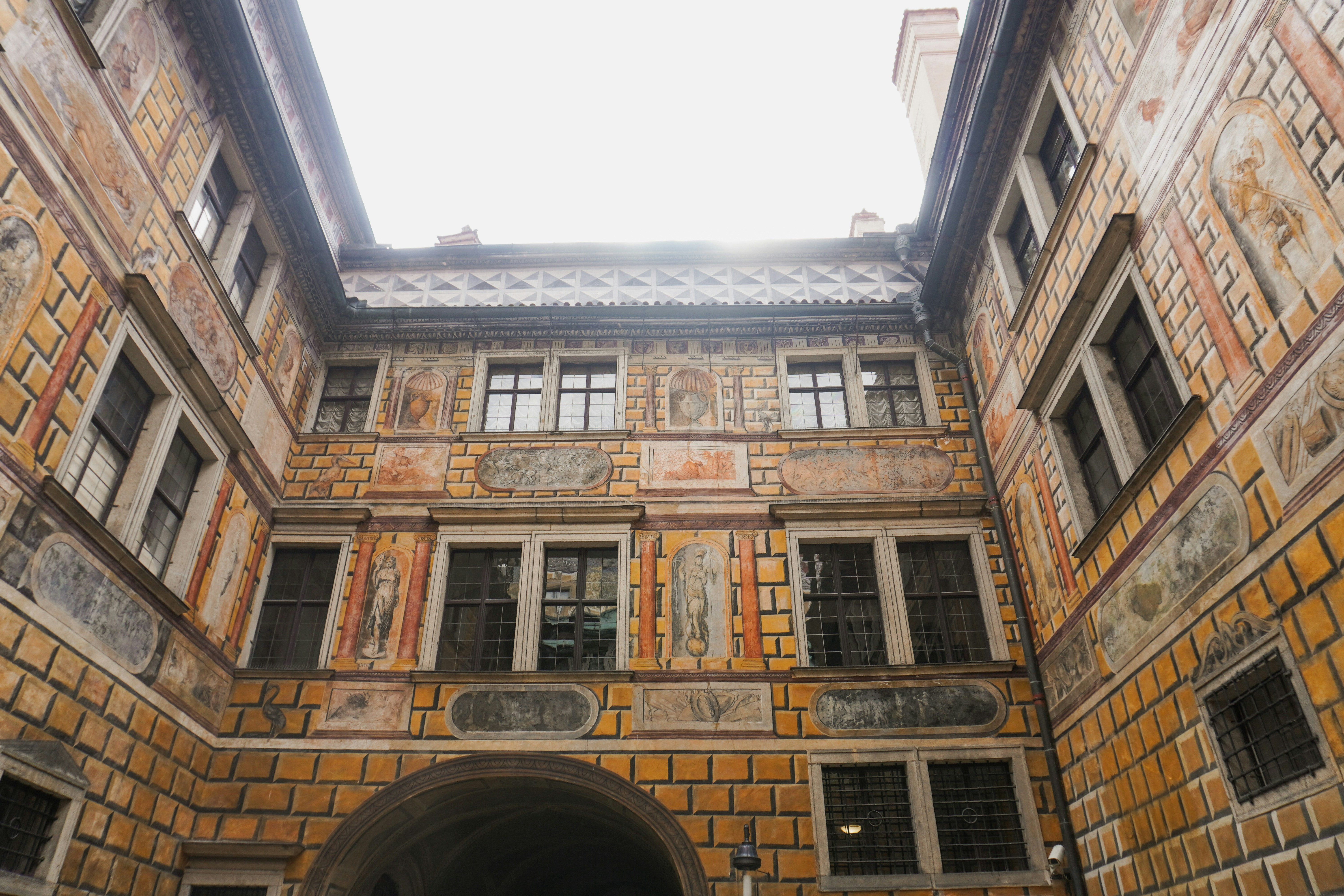 Archway Between Frescoed Brick Facades in a Quiet Courtyard