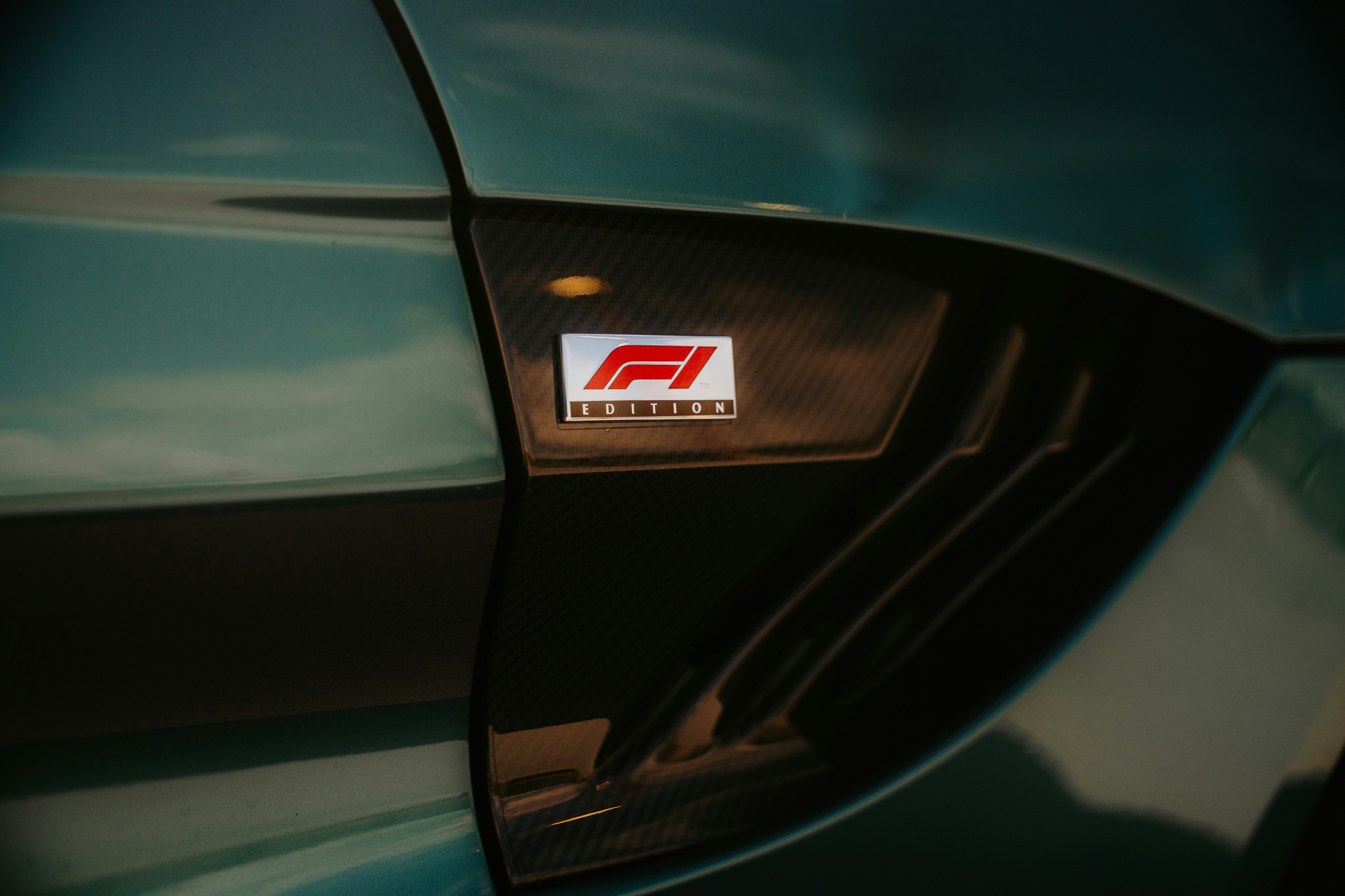 Close-up of a sleek car's carbon fiber panel featuring the F1 Edition badge, highlighting its racing lineage.