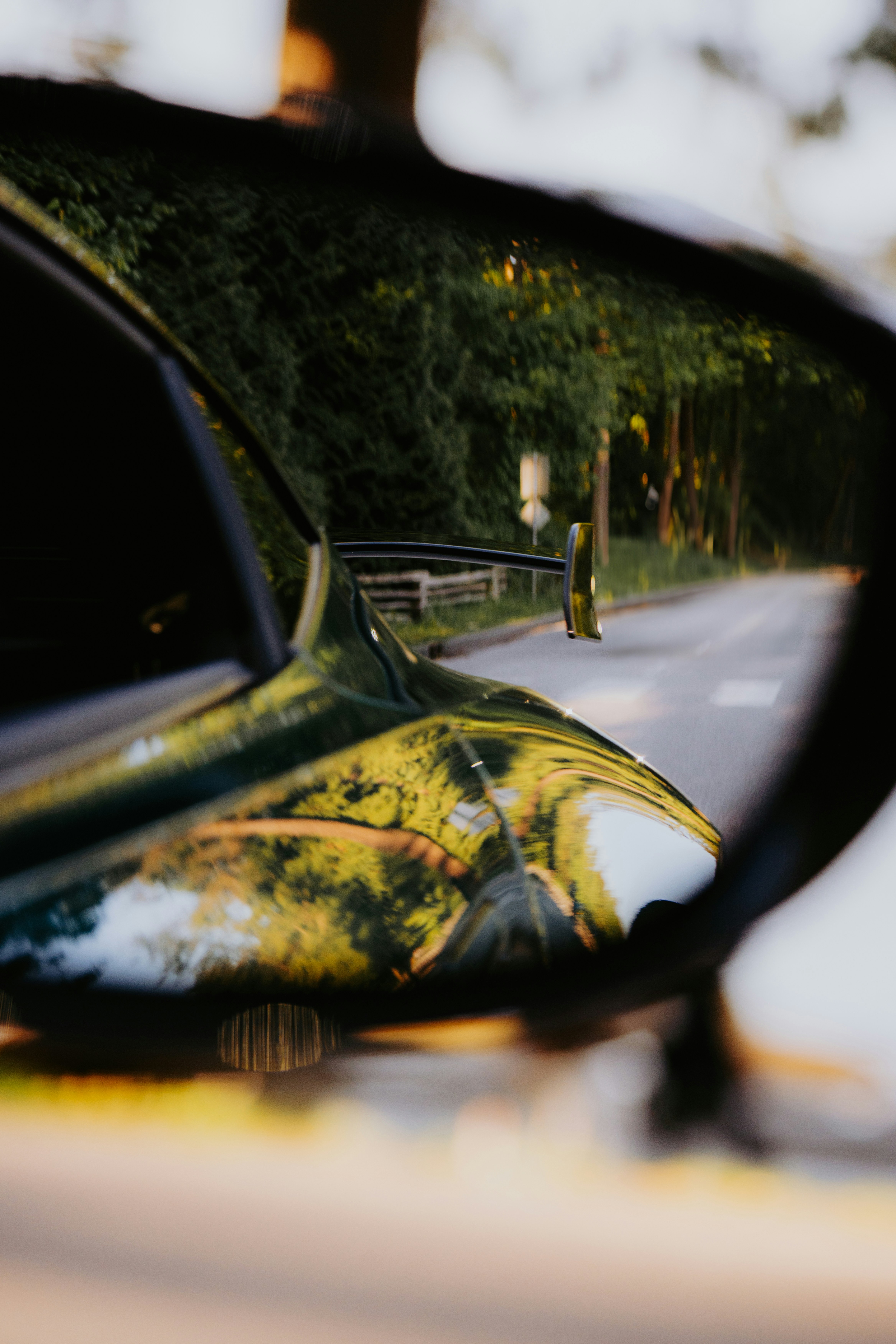 Side mirror Reflection: A Green Car’s Glimpse Along a Quiet Road