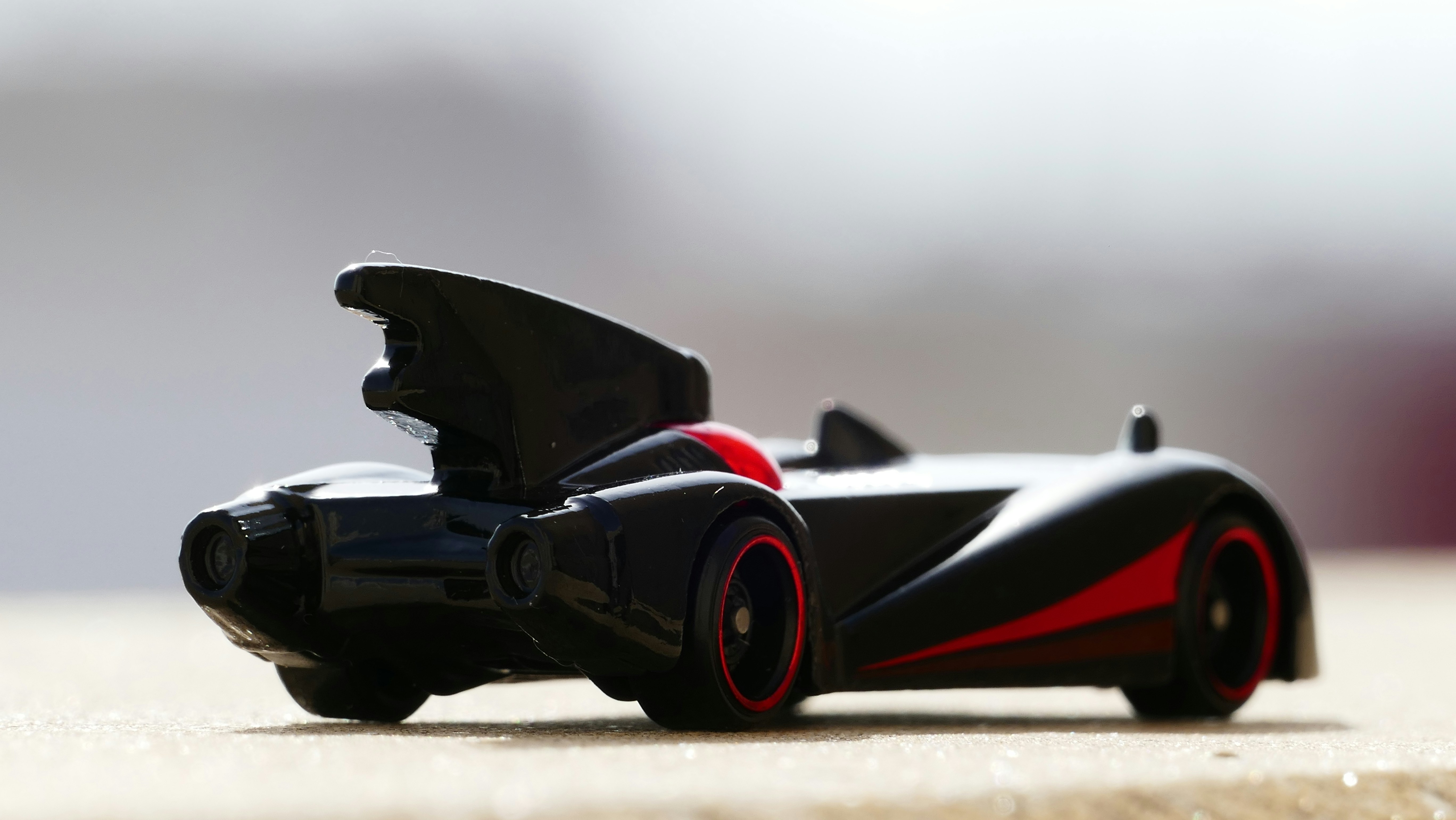 Low-angle sprint: a sleek toy racecar stops mid-tlick on sunlit pavement