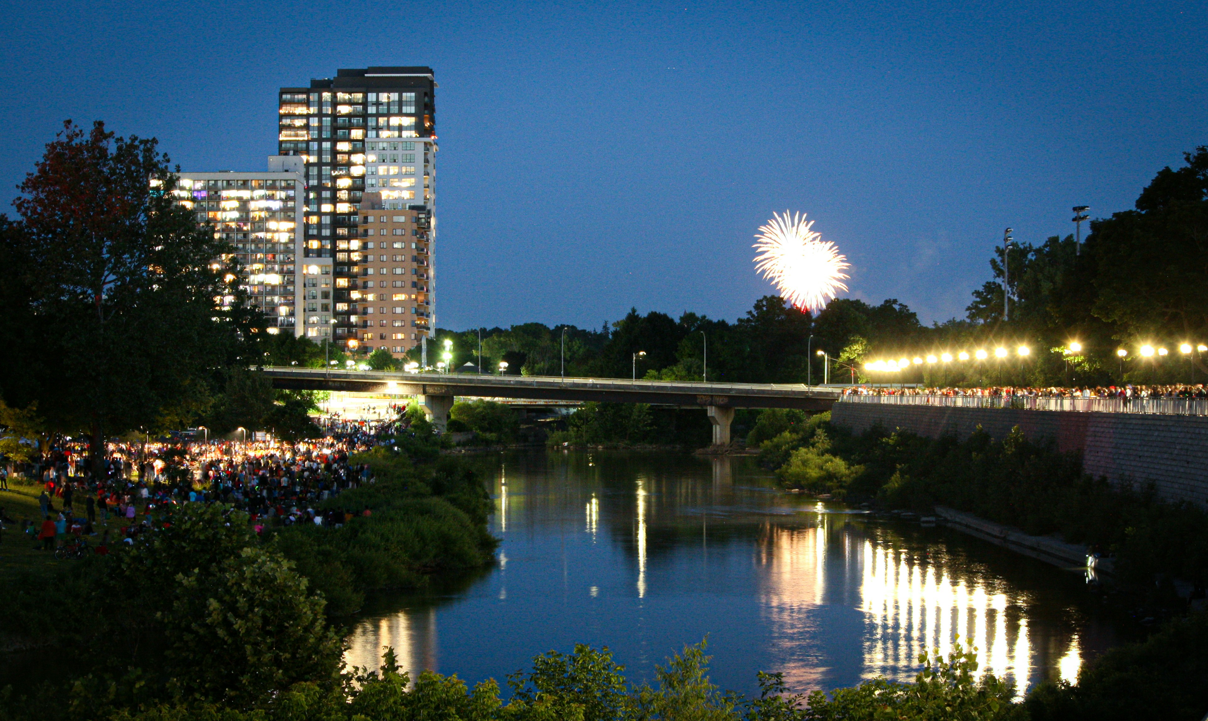Firework over the river: city lights and bridge glow
