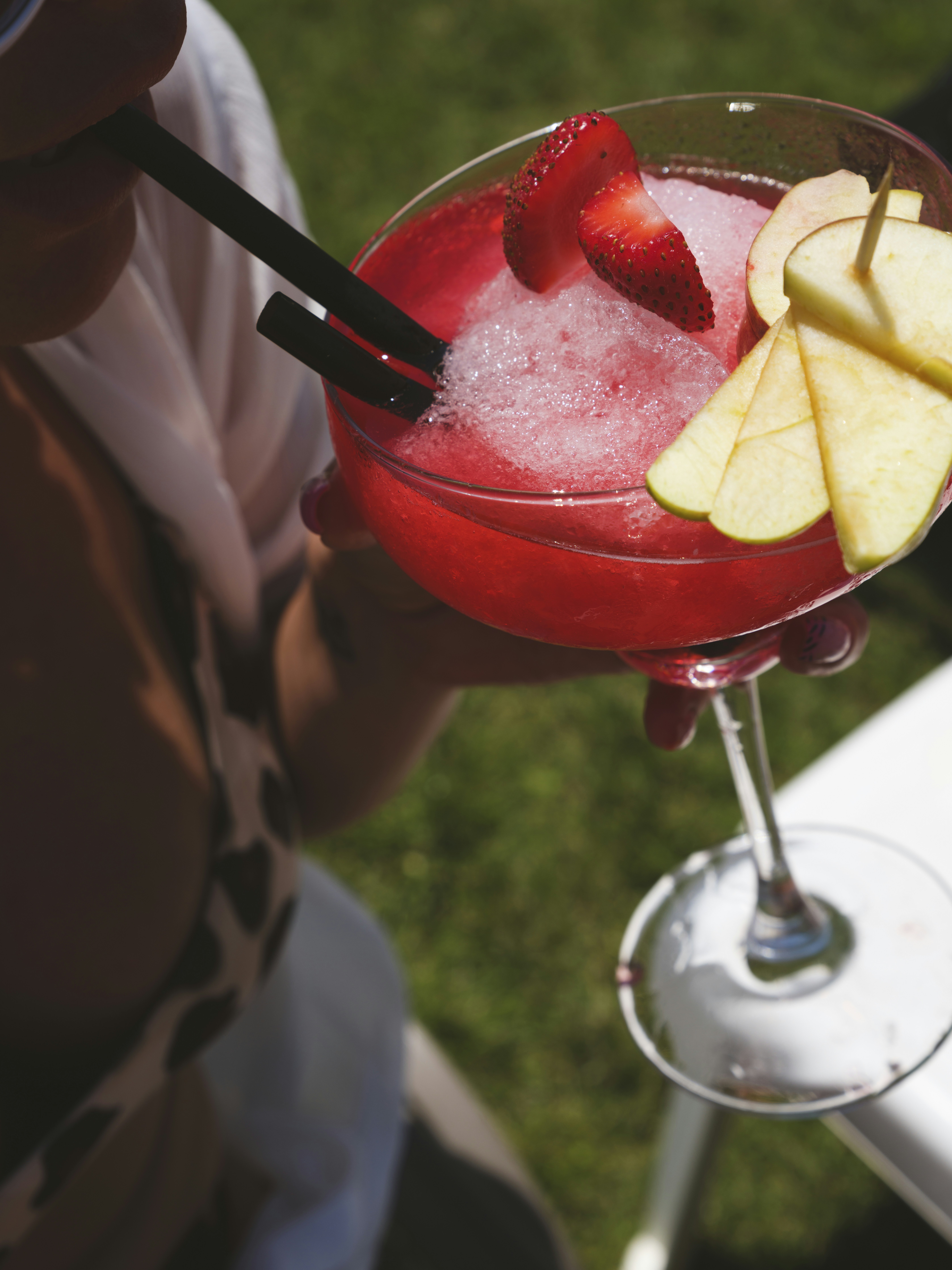 Sunlit Berry-Topped Cocktail in Hand with Side Glass