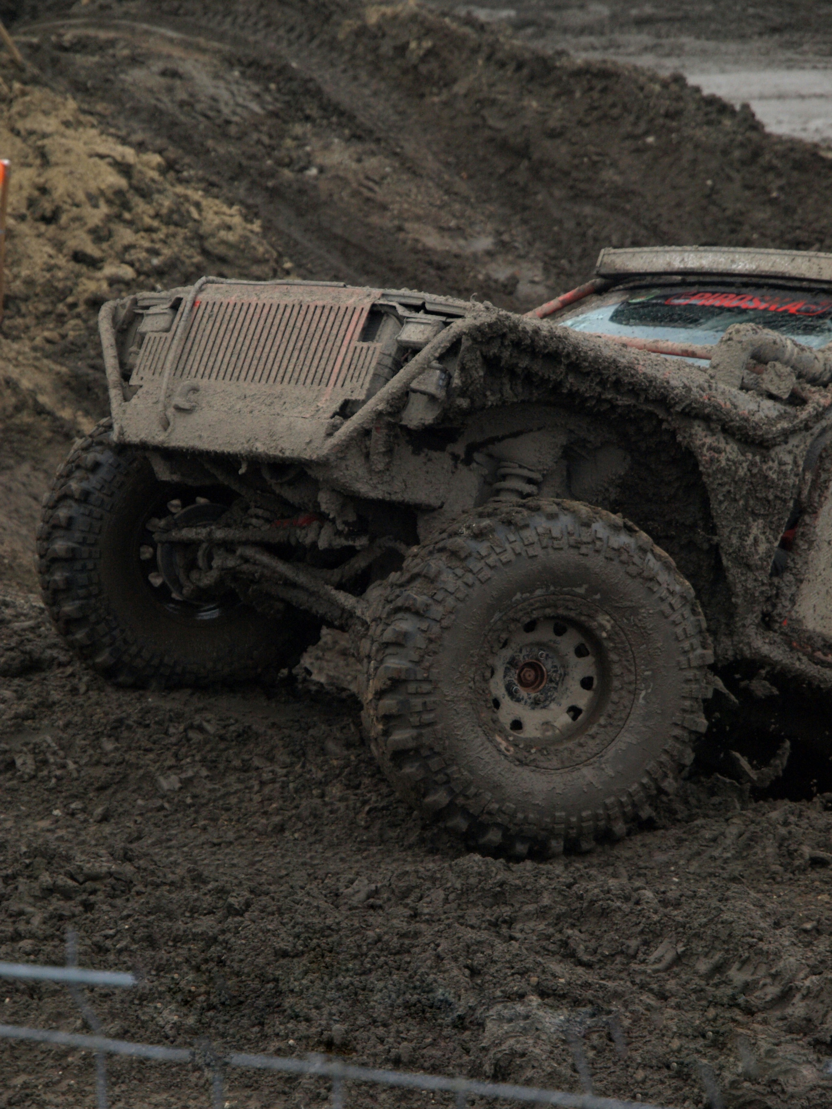 A mud-covered off-road vehicle navigates mud.