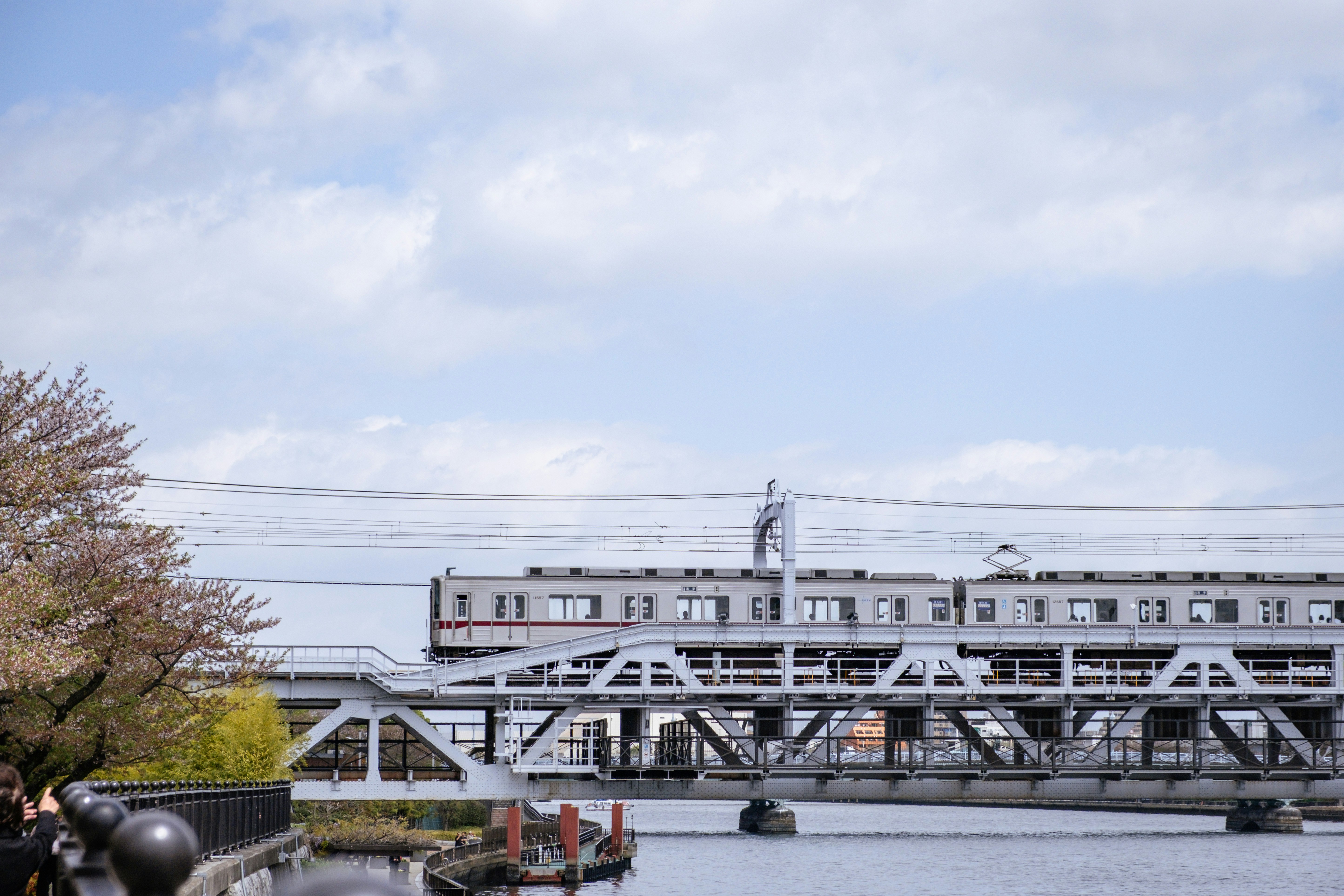 A train travels over a blue river bridge. photo – Free Japan Image on ...