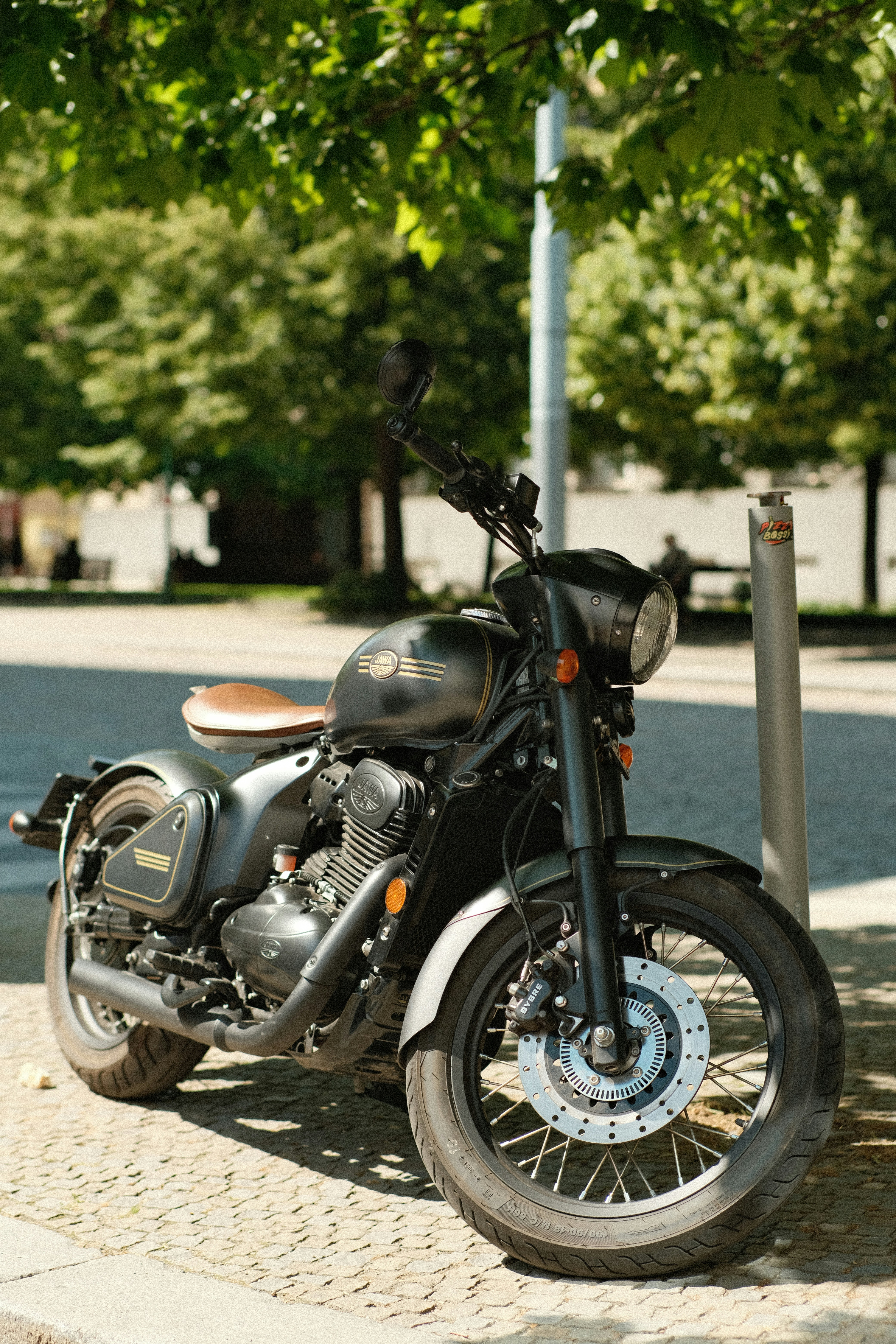 Matte Green Triumph Bonneville Pauses in a Sunlit City Square