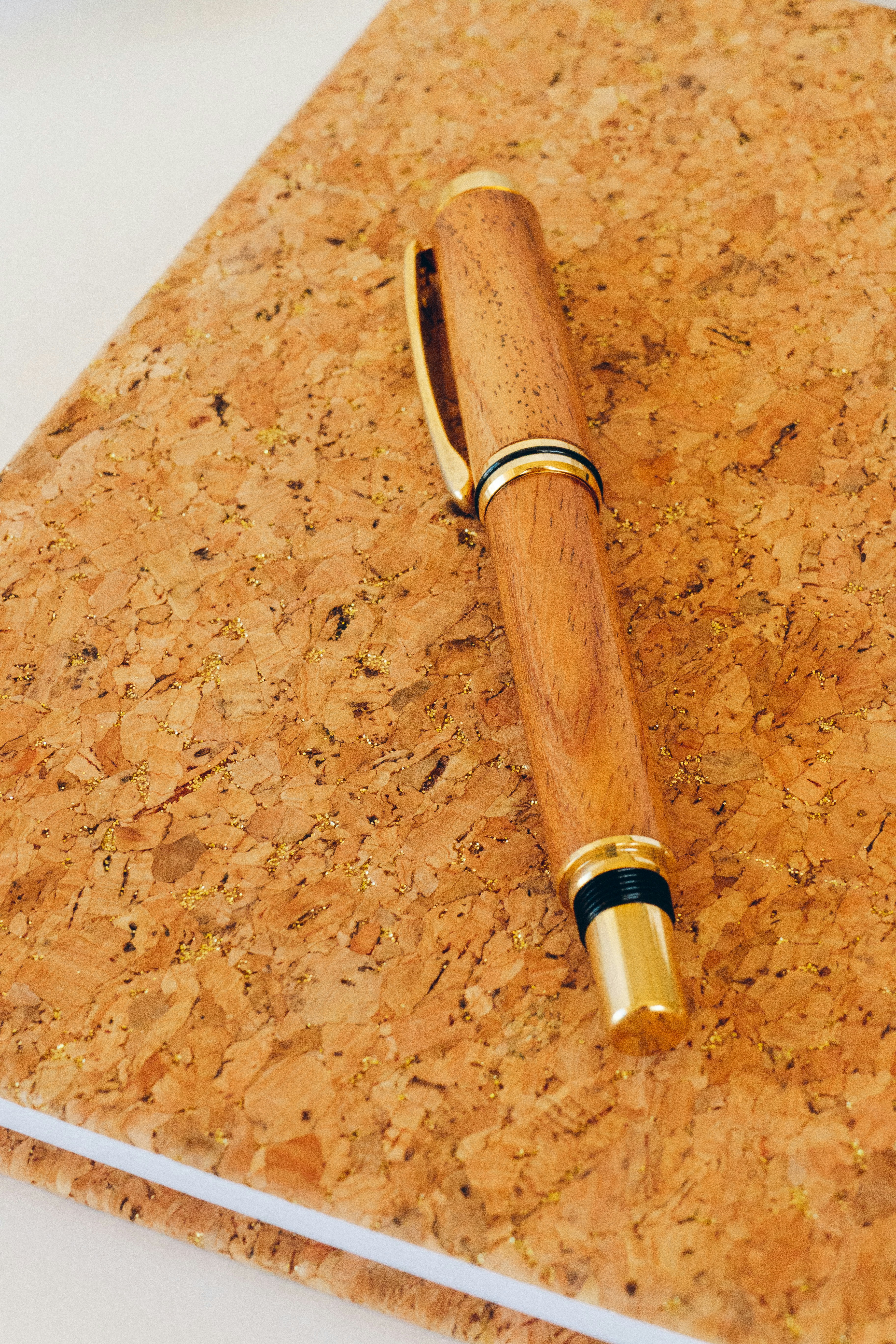 Cork notebook wirh wooden pen | Wooden pen rests atop a cork notebook.