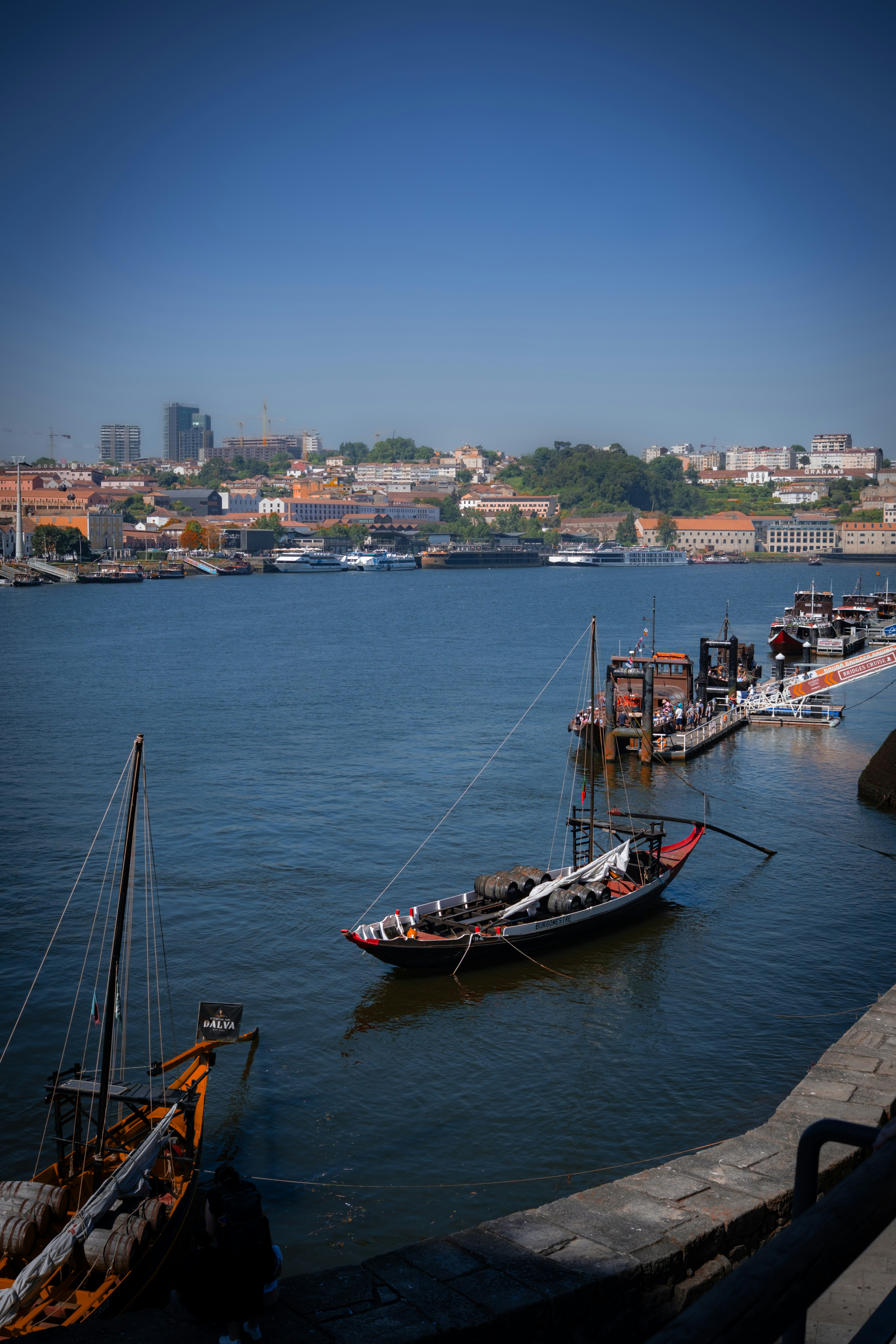 Traditional boats docked in a tranquil harbor, with a vibrant city skyline in the background. The scene captures the essence of coastal living.