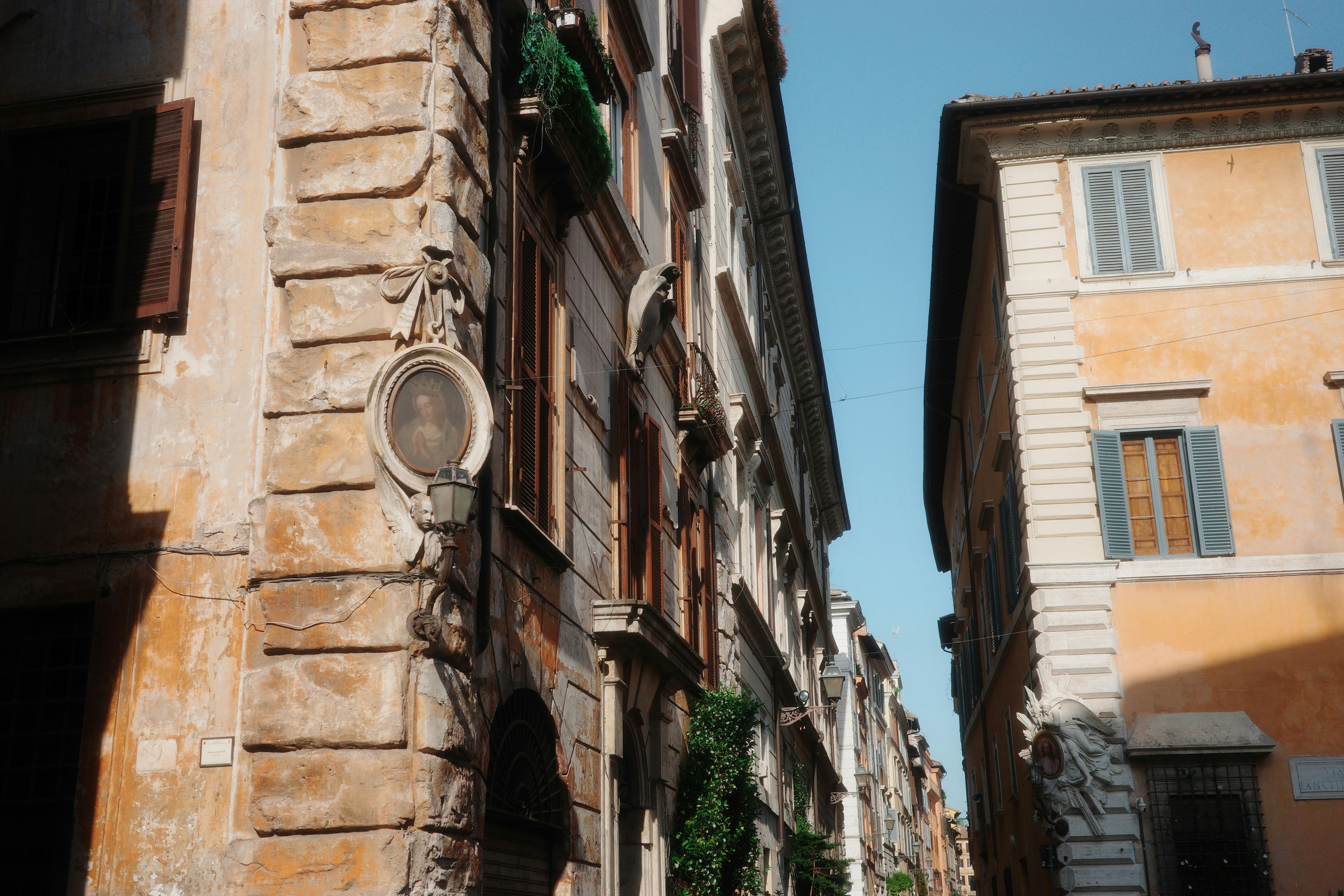 Charming narrow street lined with historic buildings adorned with greenery and architectural details, inviting exploration.