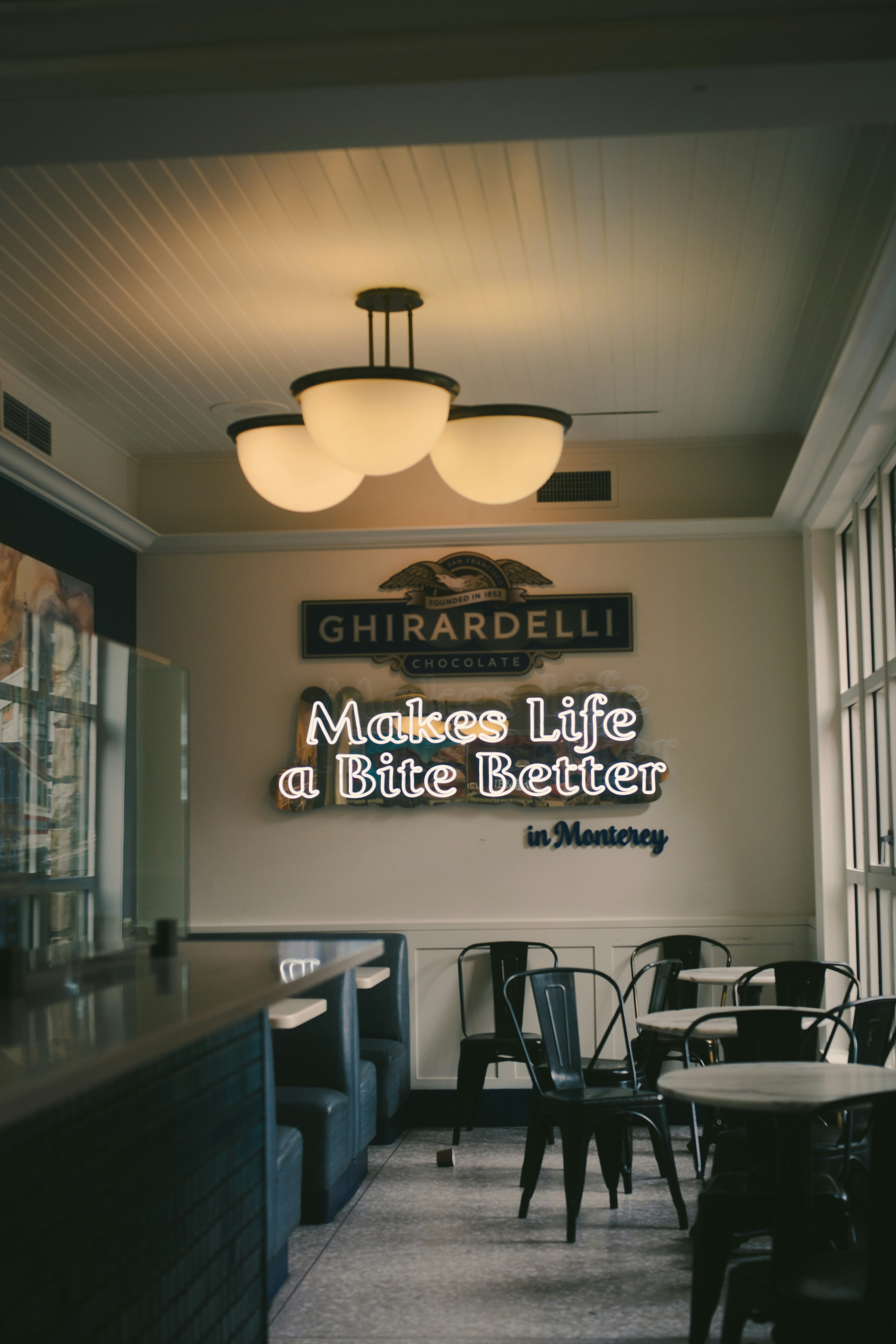 Neon Whisper Over a Monterey Café: Ghirardelli Sign and Quiet Seating