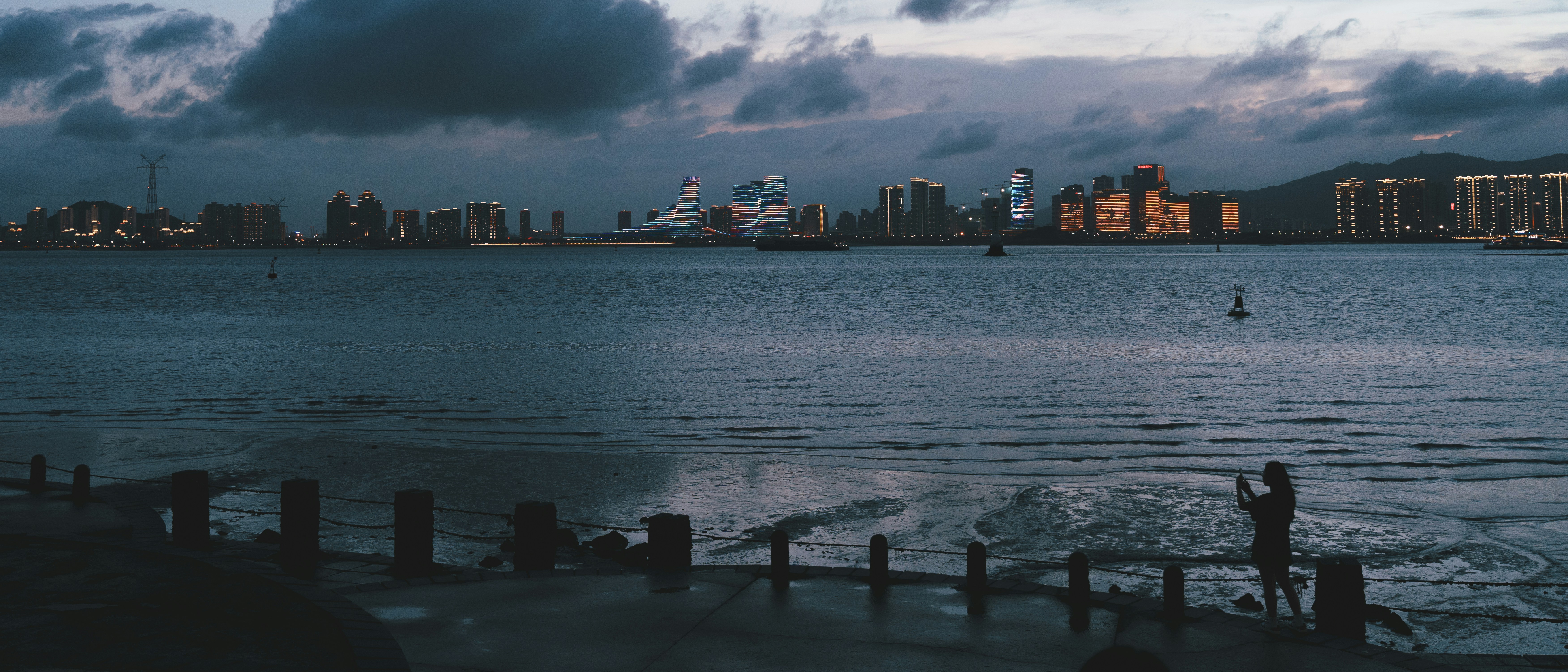 City lights shine across a tranquil sea.