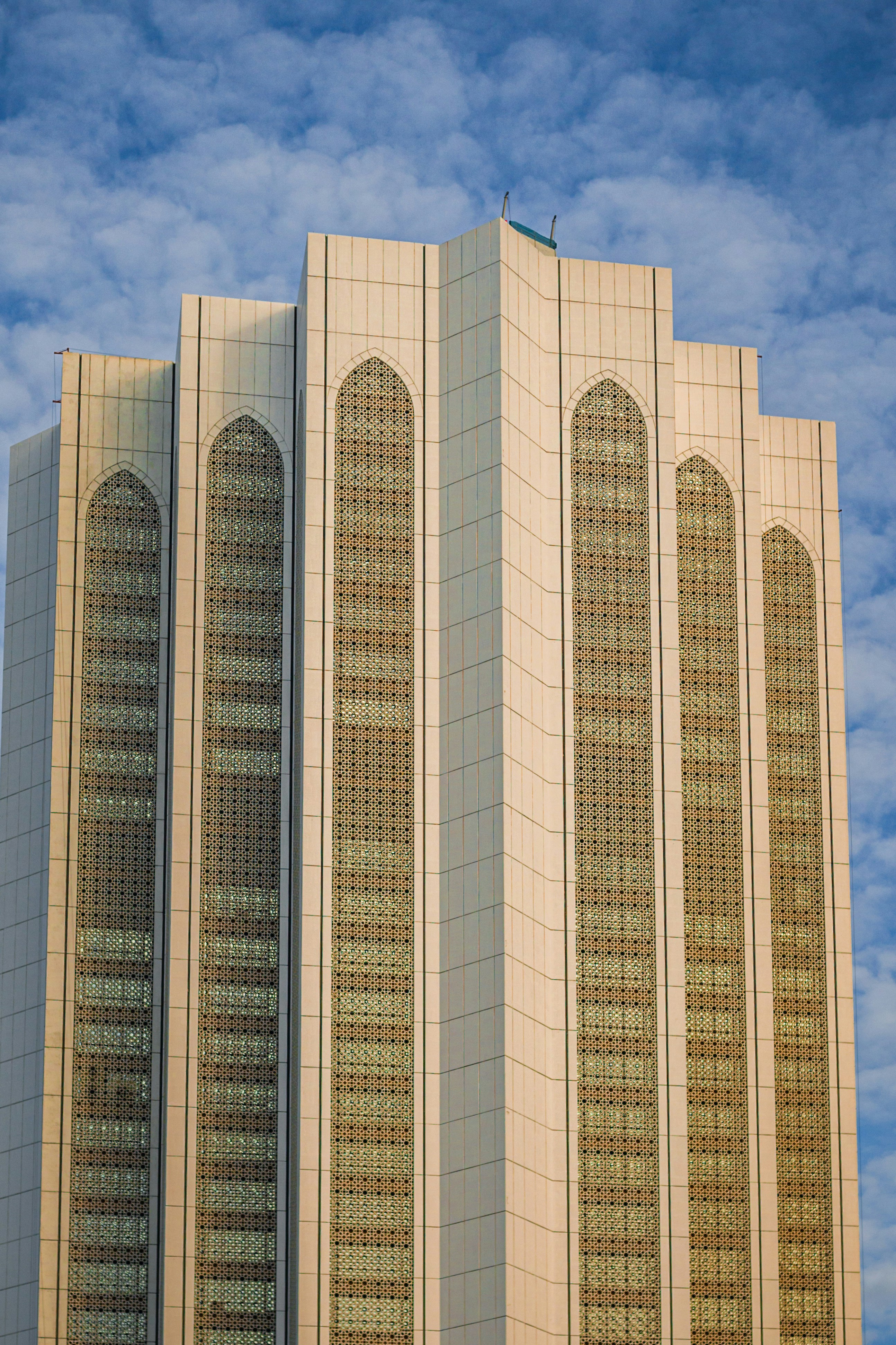 Tall, modern building with ornate arched windows against sky.