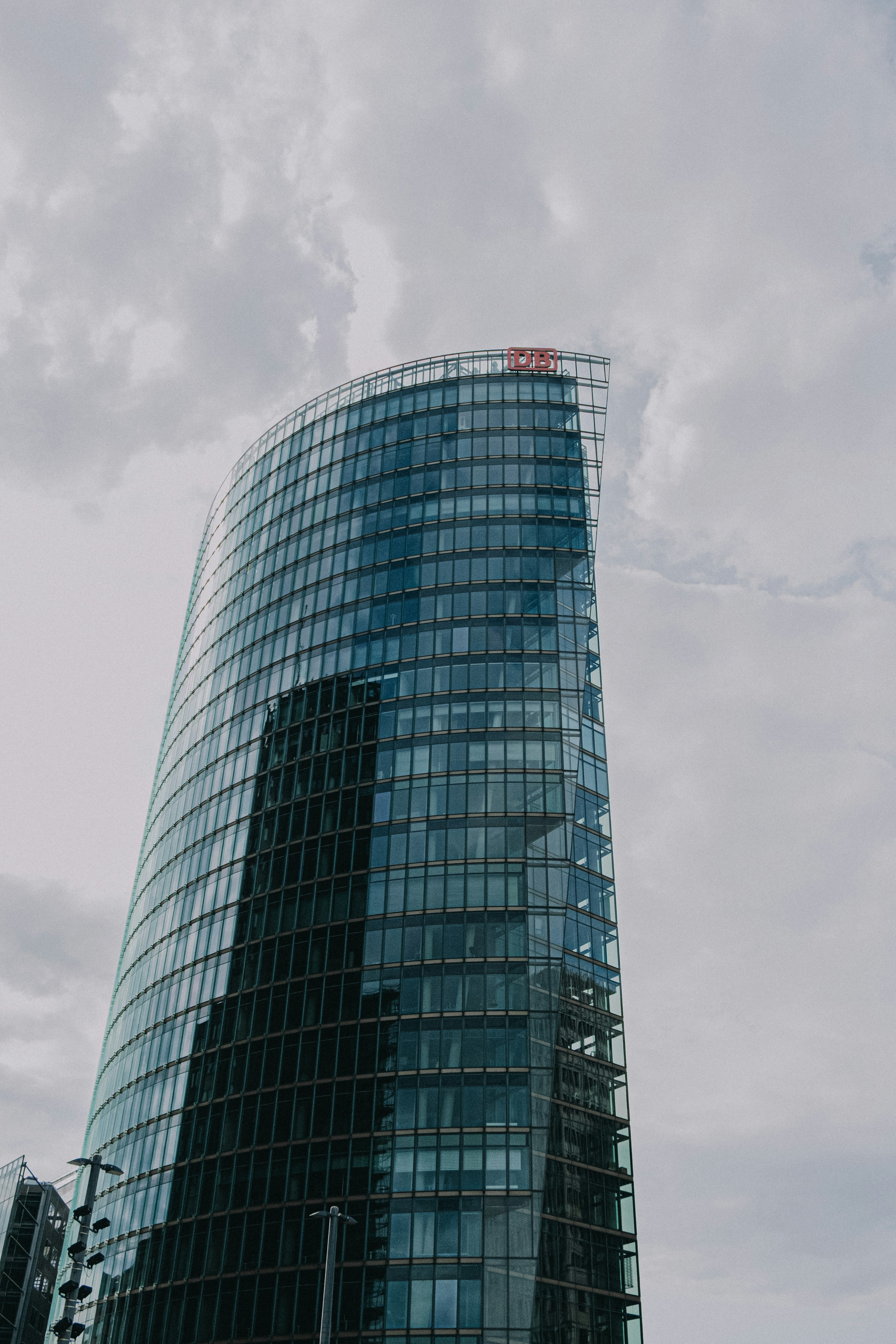 A modern glass skyscraper reaches towards the cloudy sky.