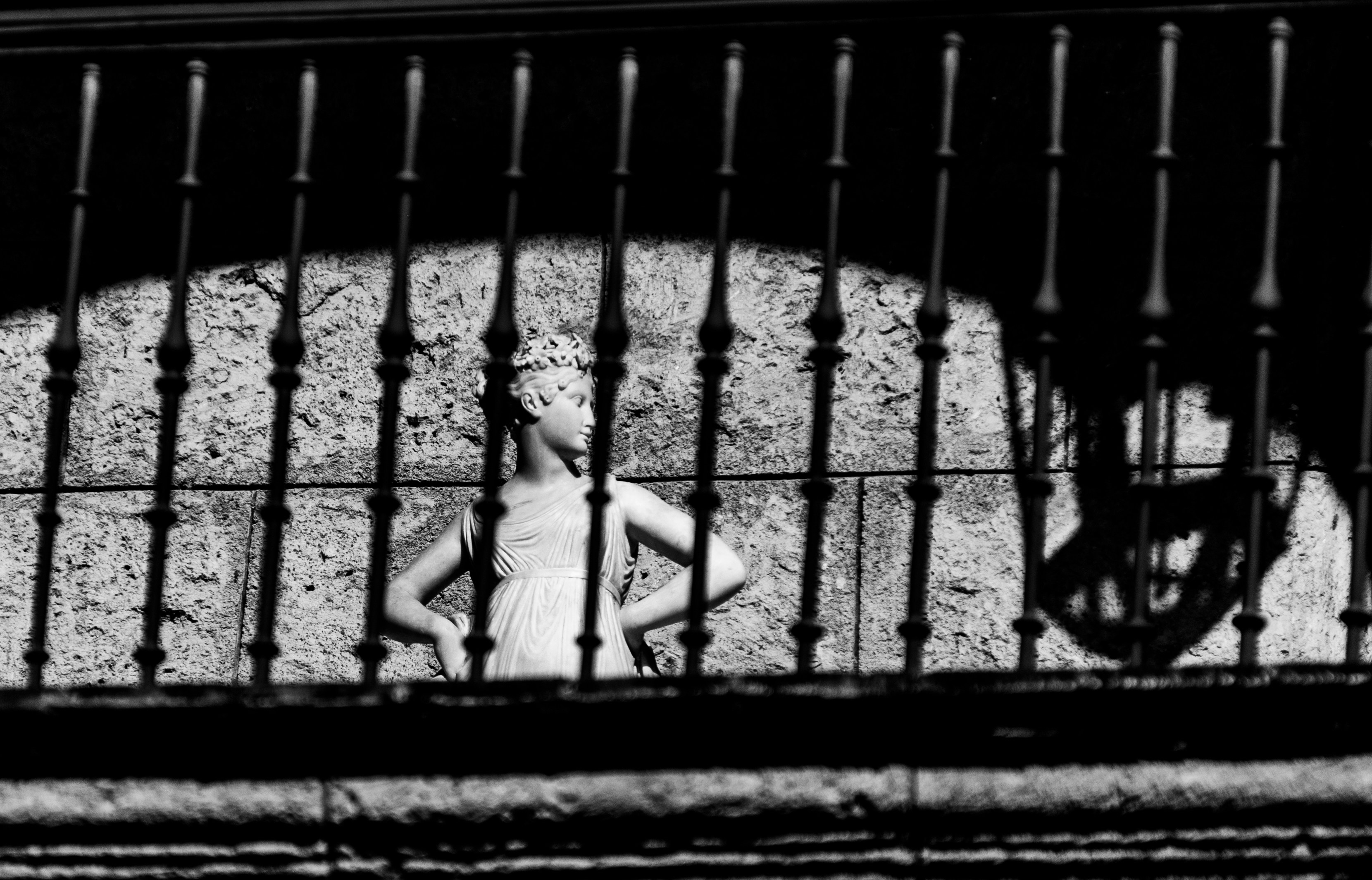 Iron Lattice, Quiet Stance: A Classical Figure Framed by Bars